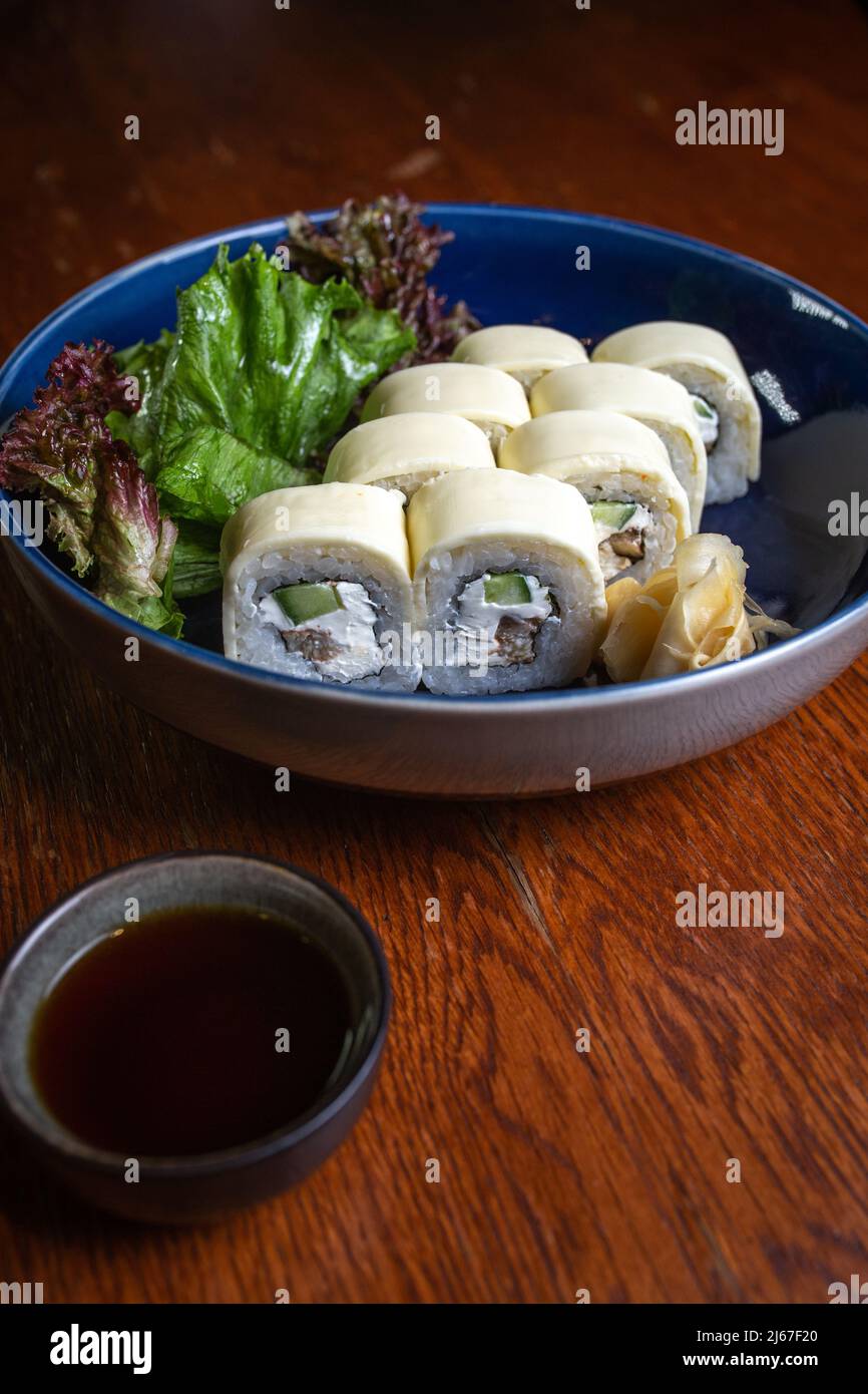 Side view of Japanese sushi roll served with ginger and wasabi on dark ...