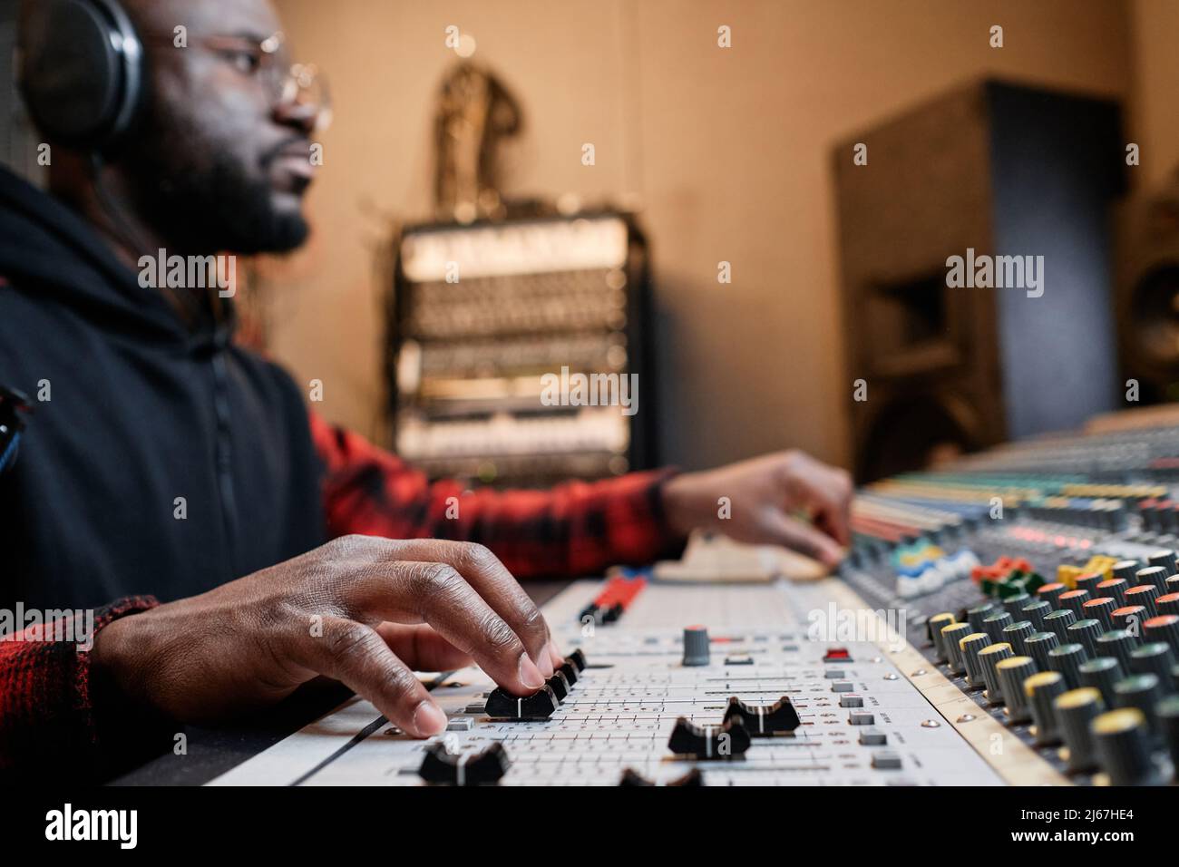 African American music producer working in record studio adjusting ...