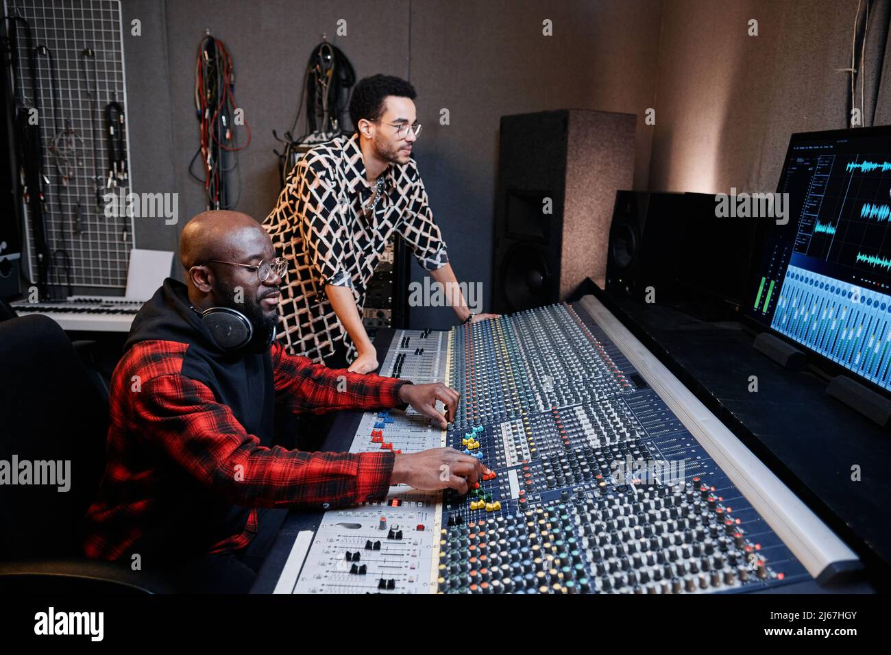 Mature Black music producer and young male singer working together on ...