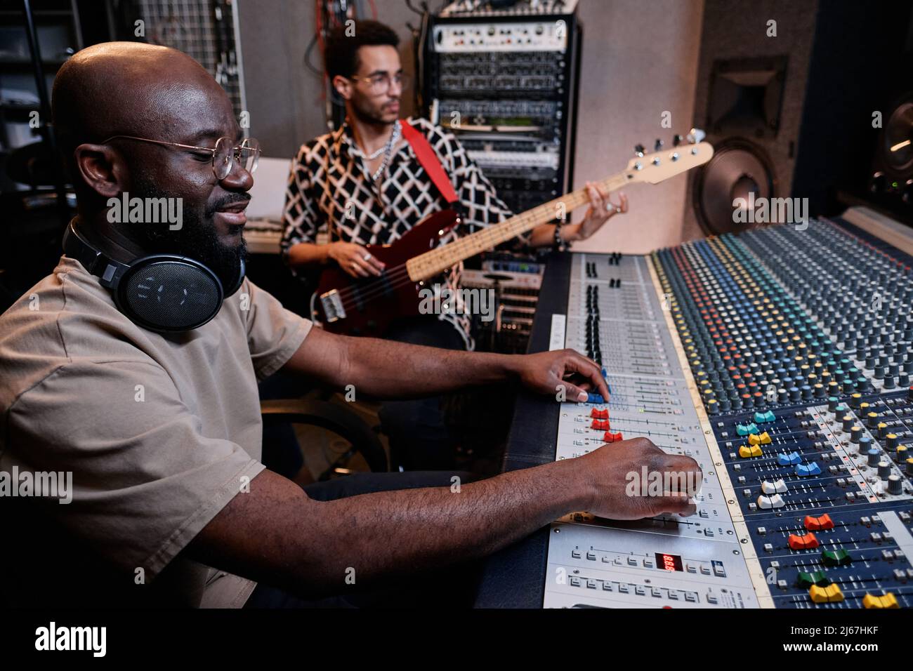Modern young Black musician playing electric guitar while sound ...