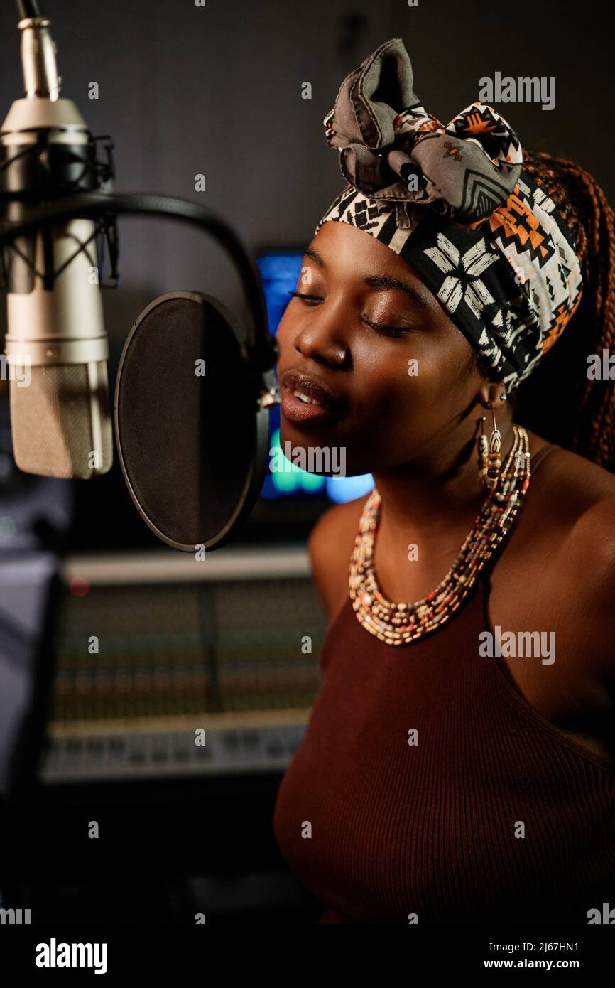 Portrait of modern young African American female singer standing in ...