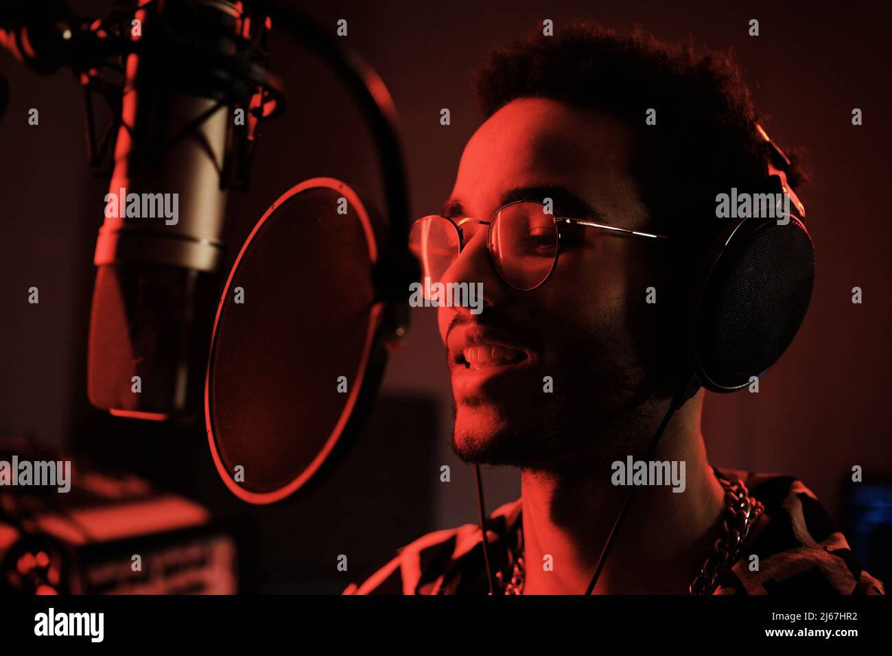 Close-up of handsome young Black singer standing in front of microphone ...