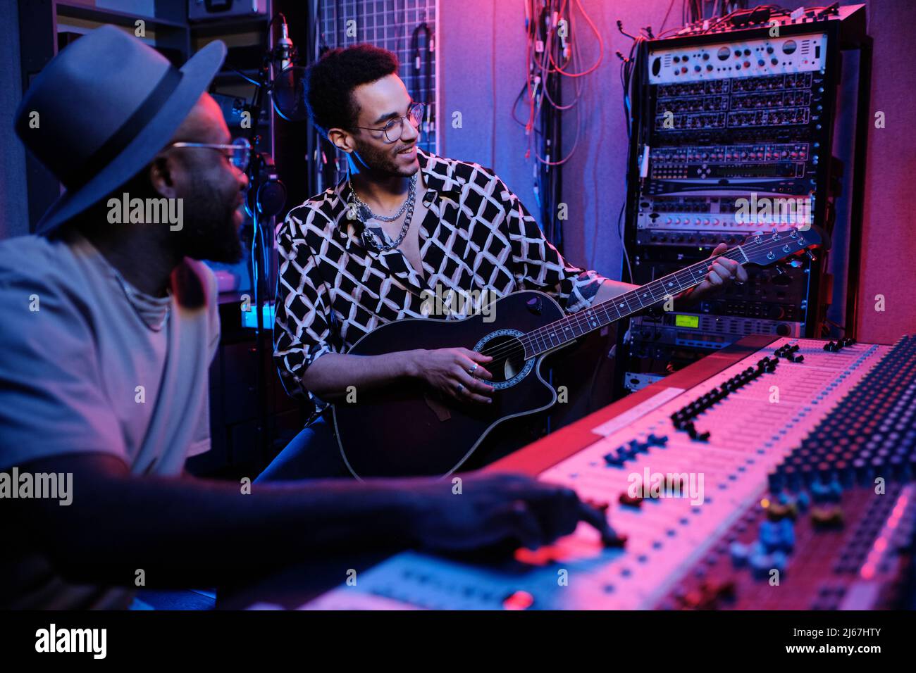 Mature Black music producer and young guitar player enjoying working on ...