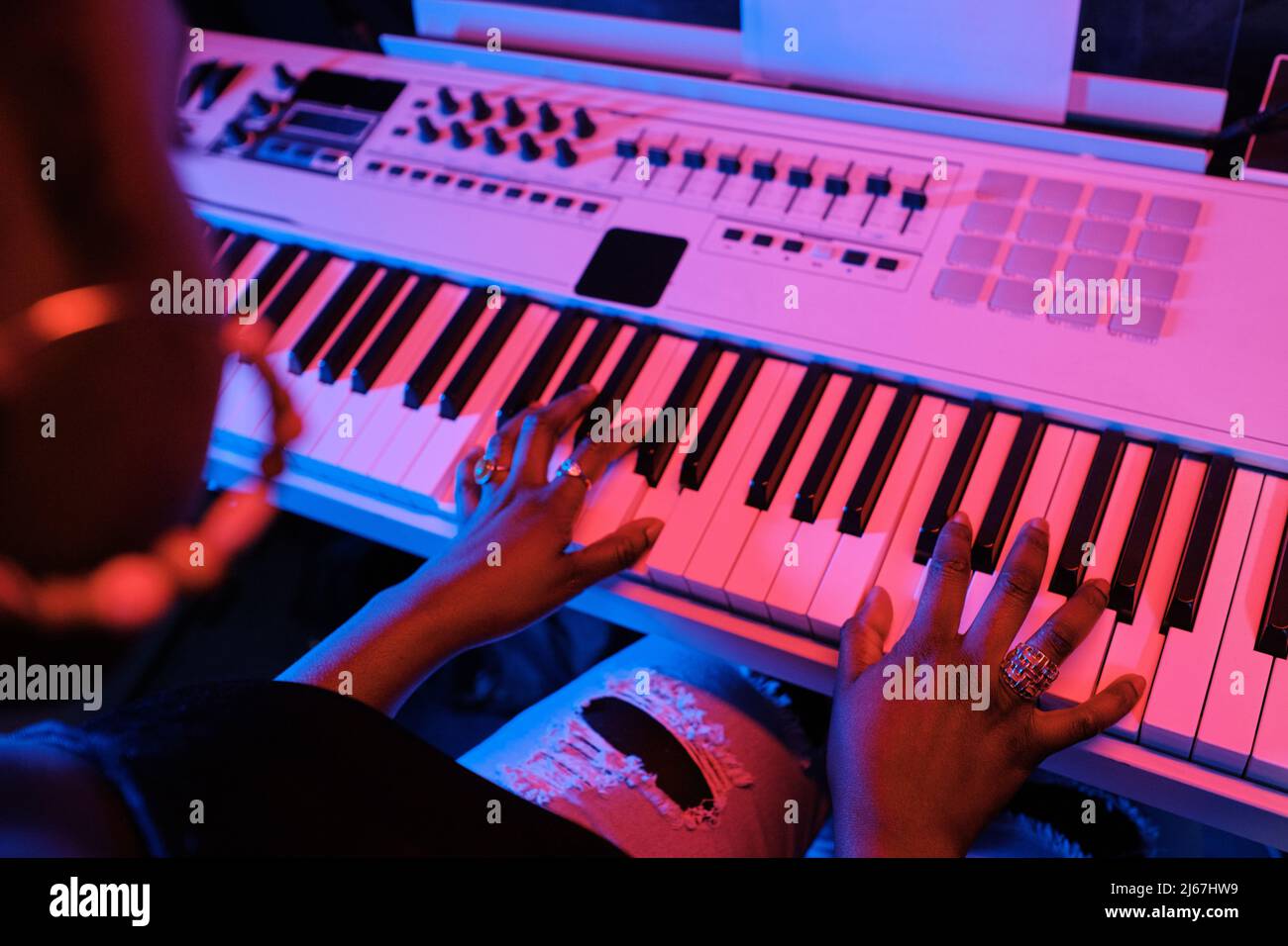 High angle view of unrecognizable young Black woman playing synthesizer ...