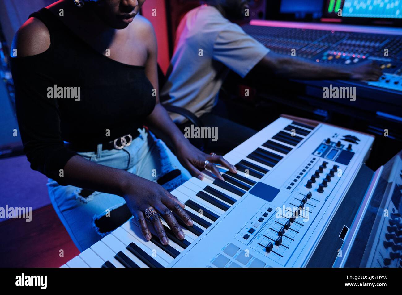 African American woman playing digital keyboard while music producer ...