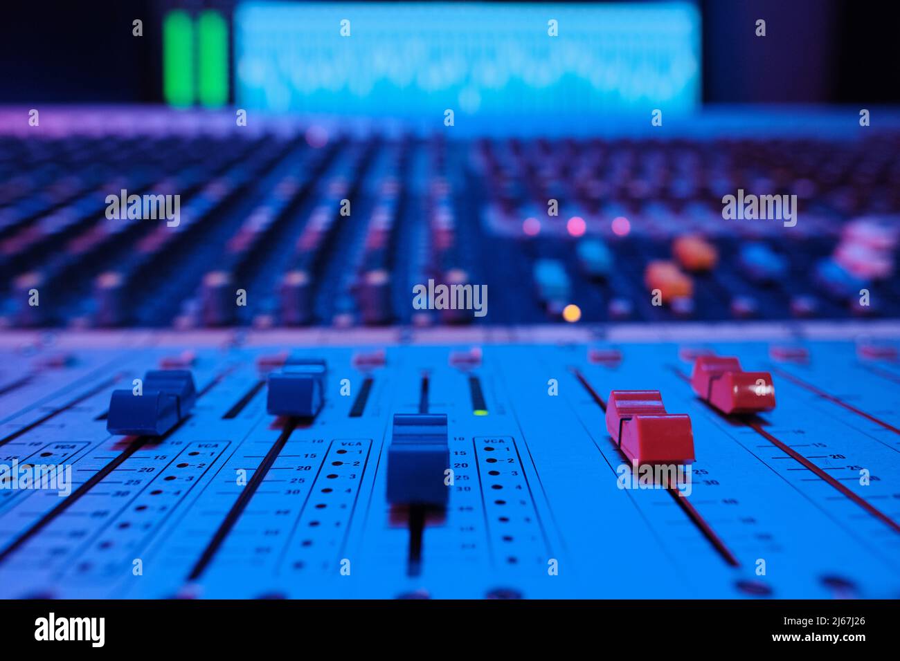 Close-up shot of mixing console buttons and sliders in blue neon light ...