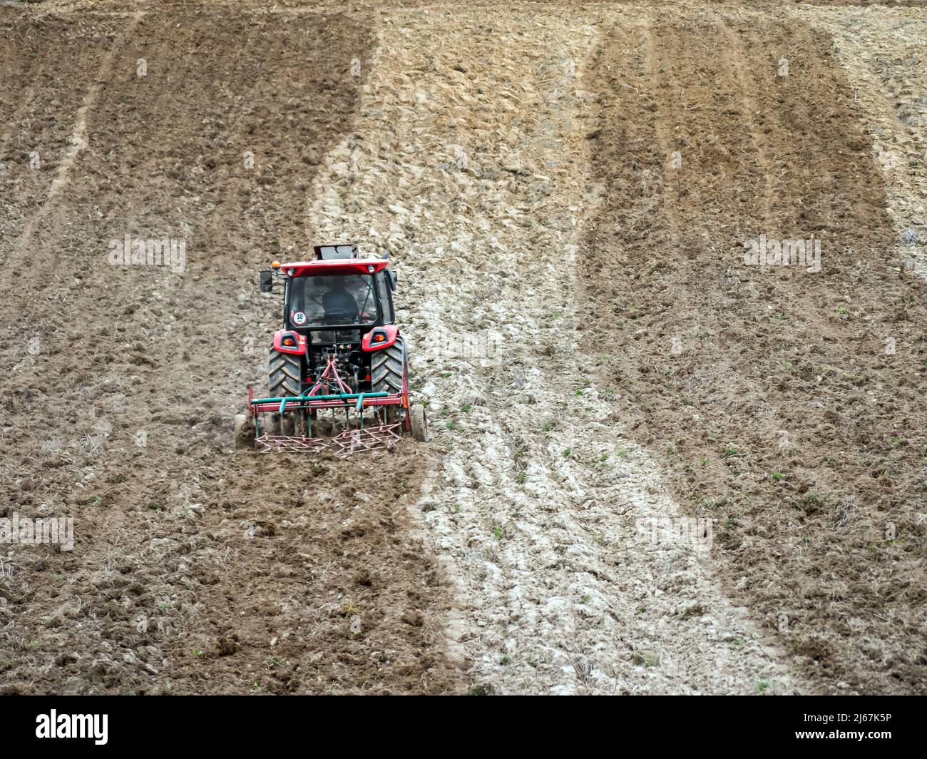 Aerial view of farm tractor harrowing arable field Stock Photo - Alamy