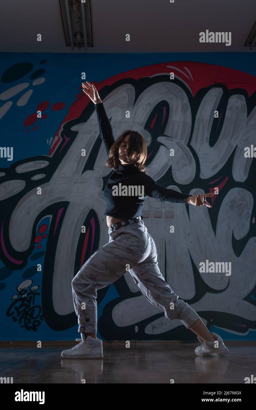 Silhouette of young woman hiphop dancer (breakdancer)dancing on graffiti studio background ...