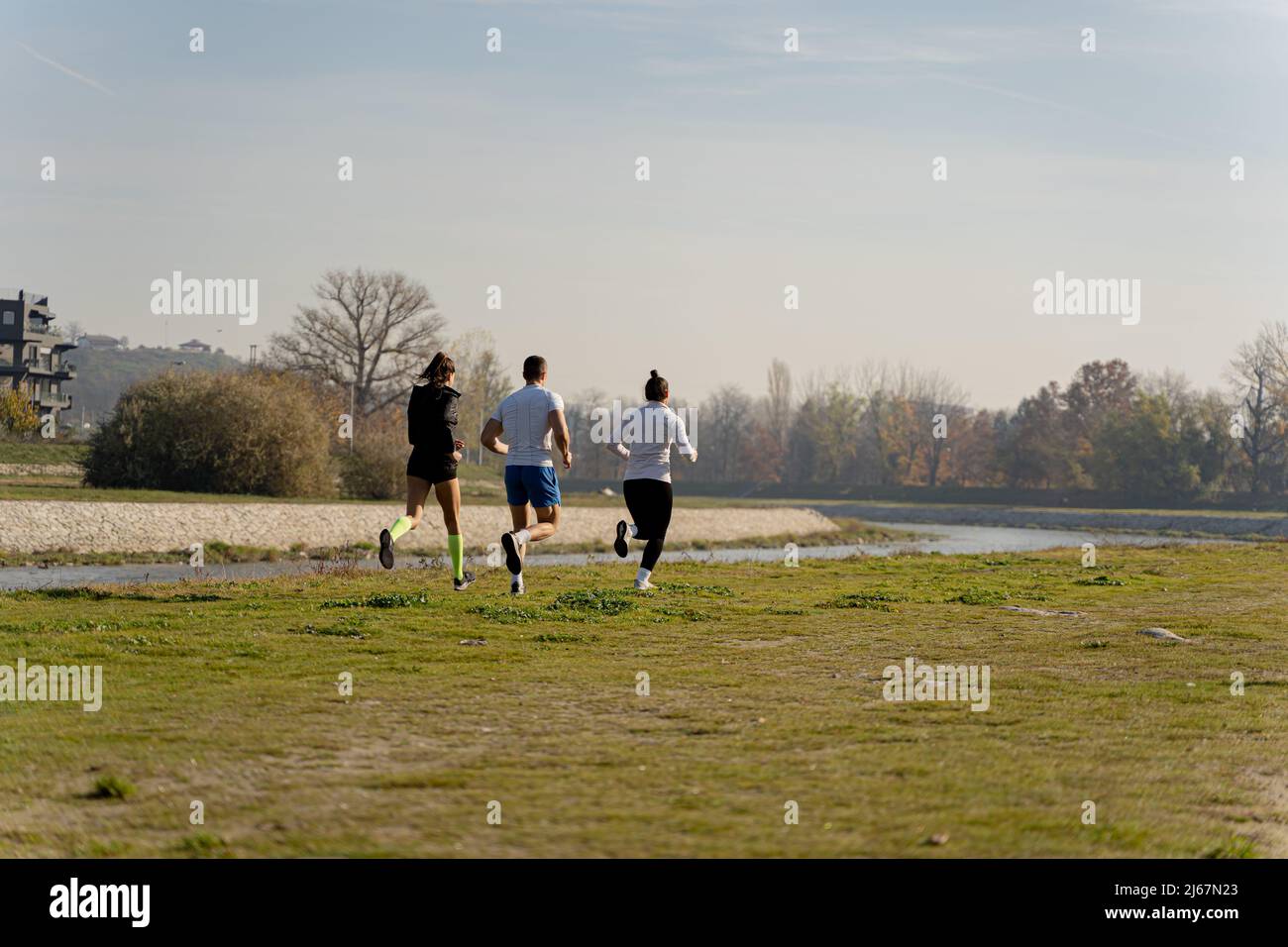 Three amazing and attractive friends are jogging and smiling together ...