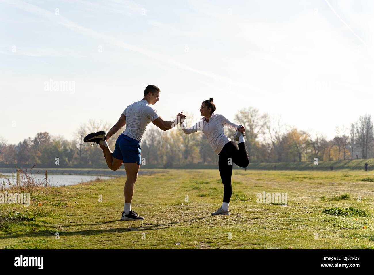 Two amazing and fit friends are balancing on one leg while holding each ...
