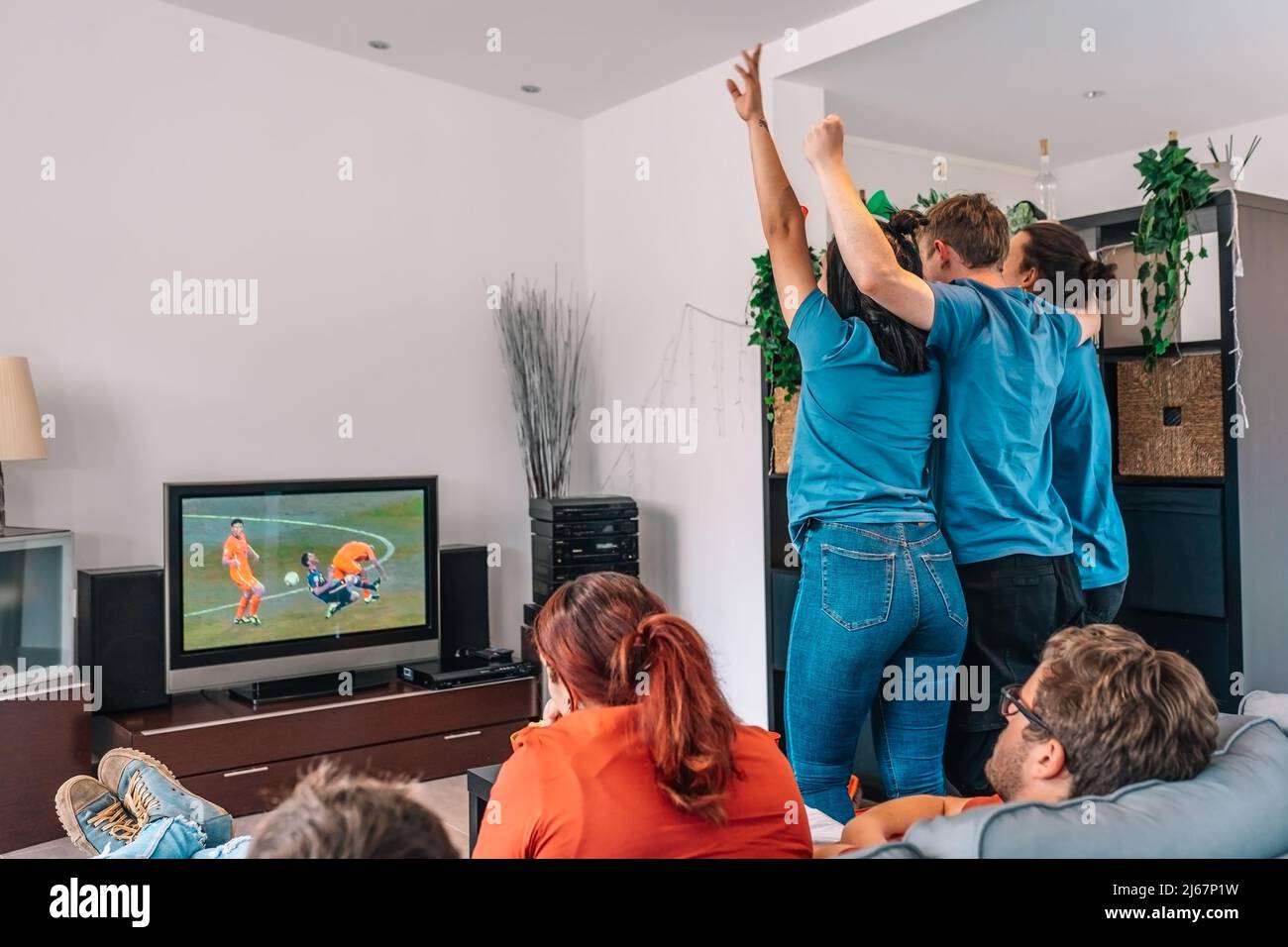 friends jumping for joy after their team's victory, watching football ...