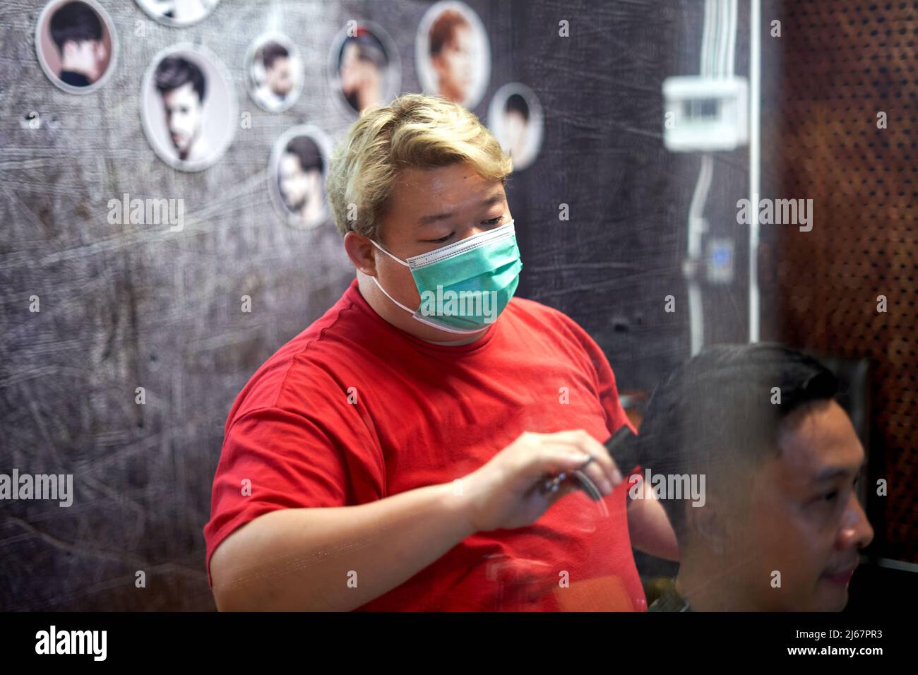 Focus on the face of a barber using mask while combing the hair of a client Stock Photo - Alamy