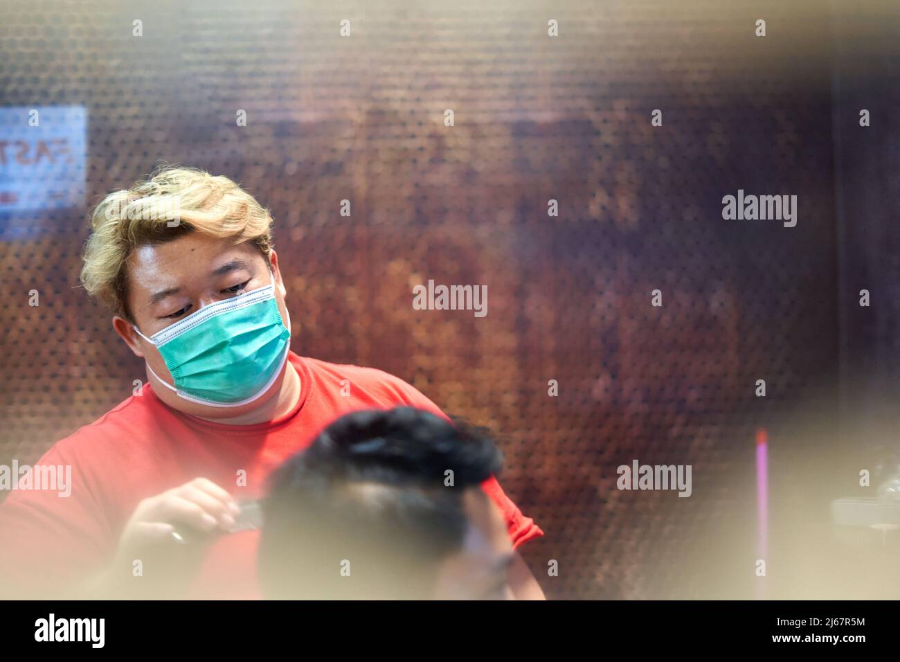 Focus on the face of an asian fat barber wearing mask while working ...