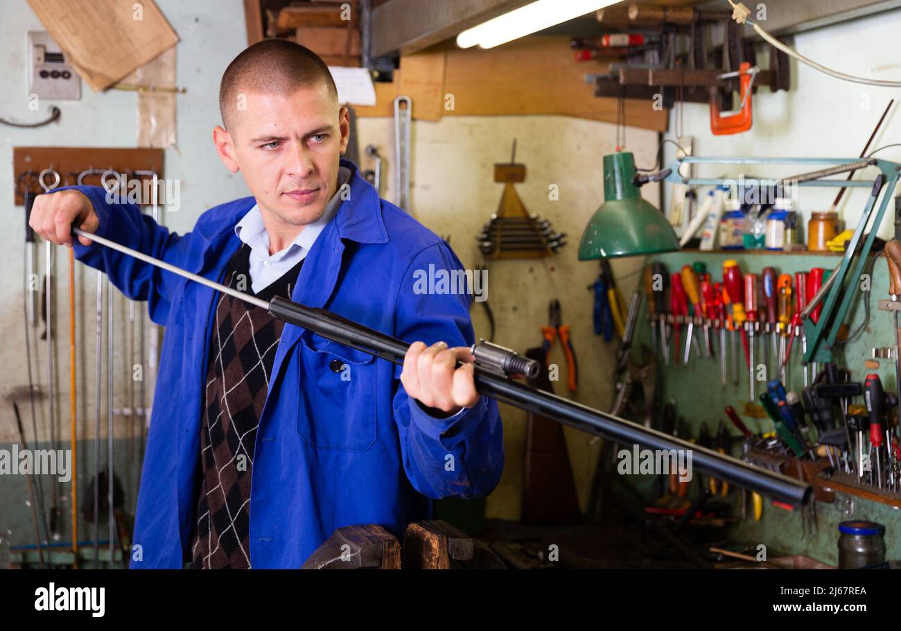 Qualified gunsmith using ramrod to cleaning shotgun barrel Stock Photo ...