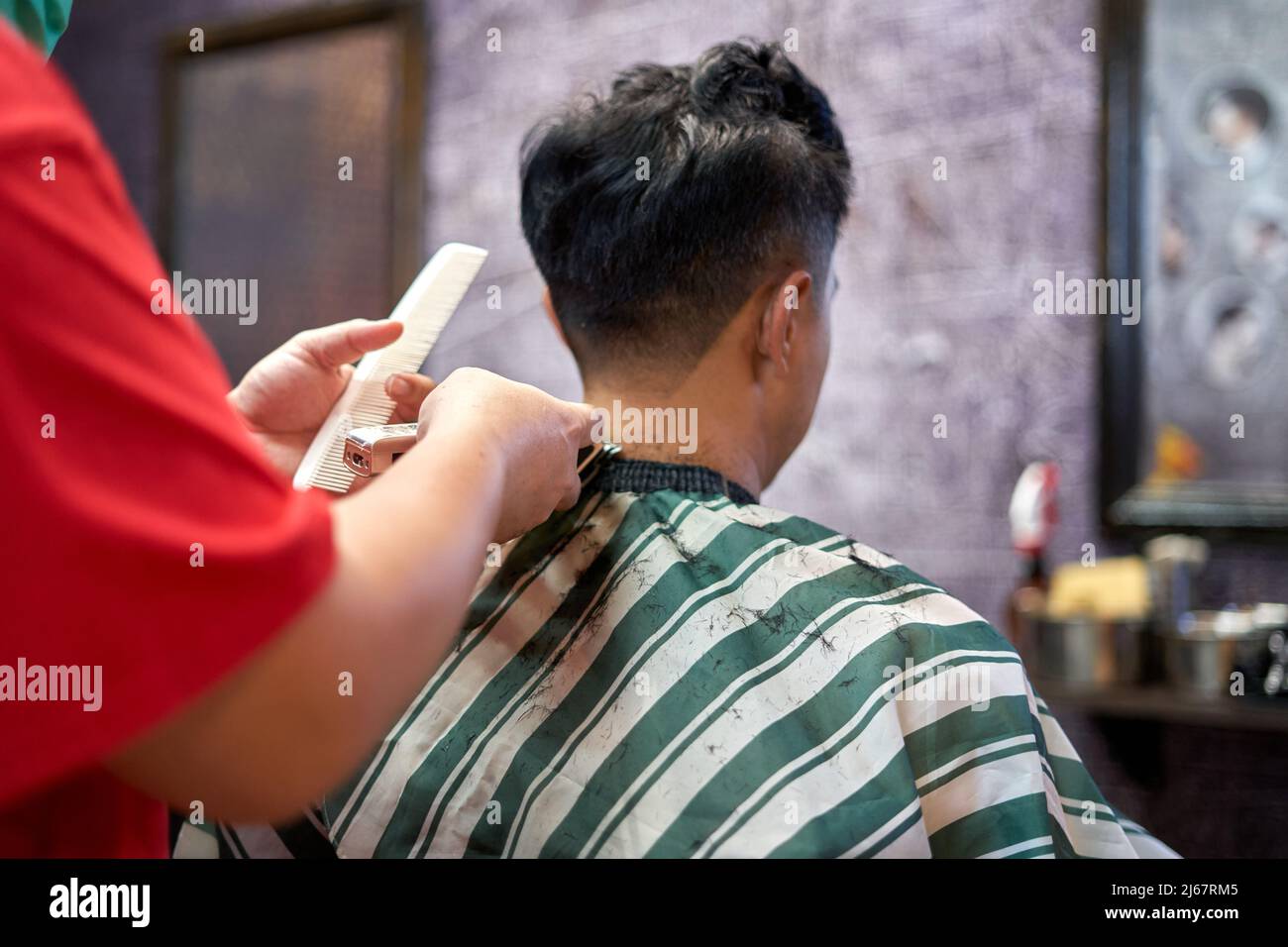 Client sitting on a chair while a barber shaving her nape Stock Photo ...