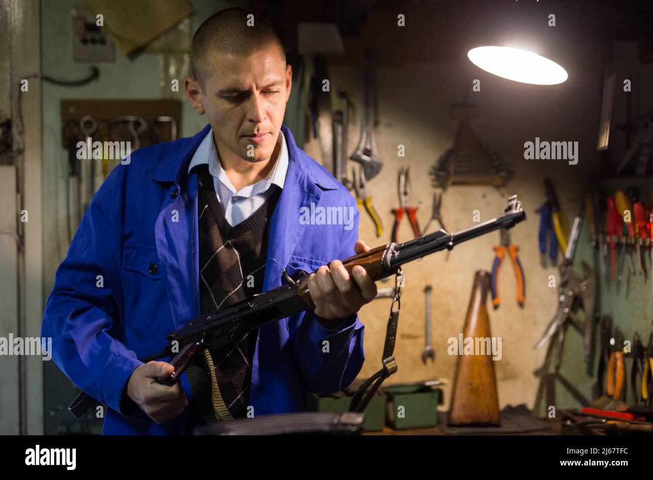 Gunsmith with Kalashnikov assault rifle in weapons workshop Stock Photo ...