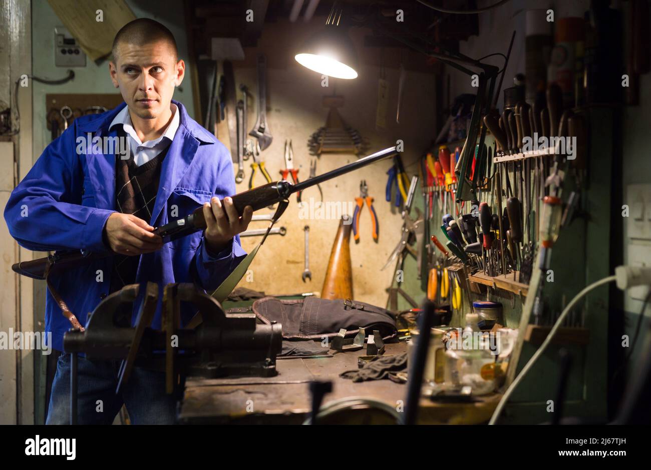 Gunsmith examines an automatic rifle before being repaired in weapons ...