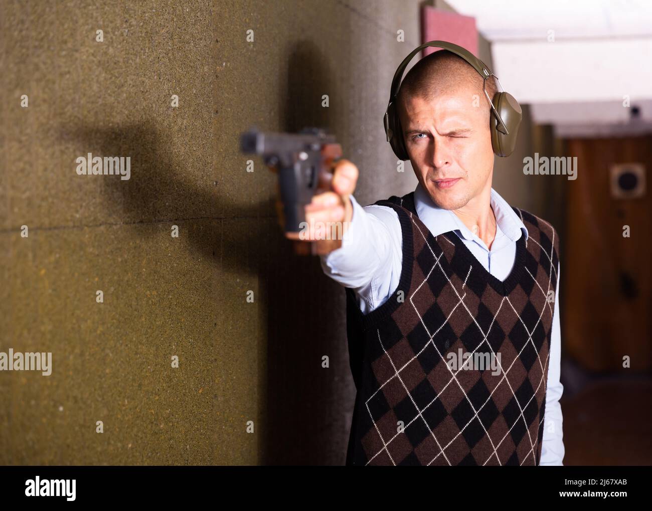 Man aiming smallbore sporting pistol at target in shooting range Stock ...