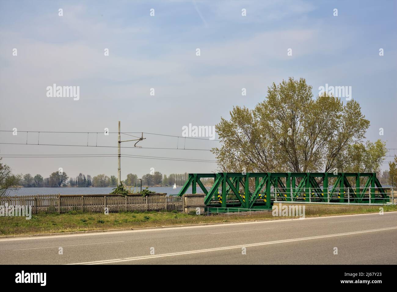 Road next to a lake and a park with railroad tracks by its edge on a ...