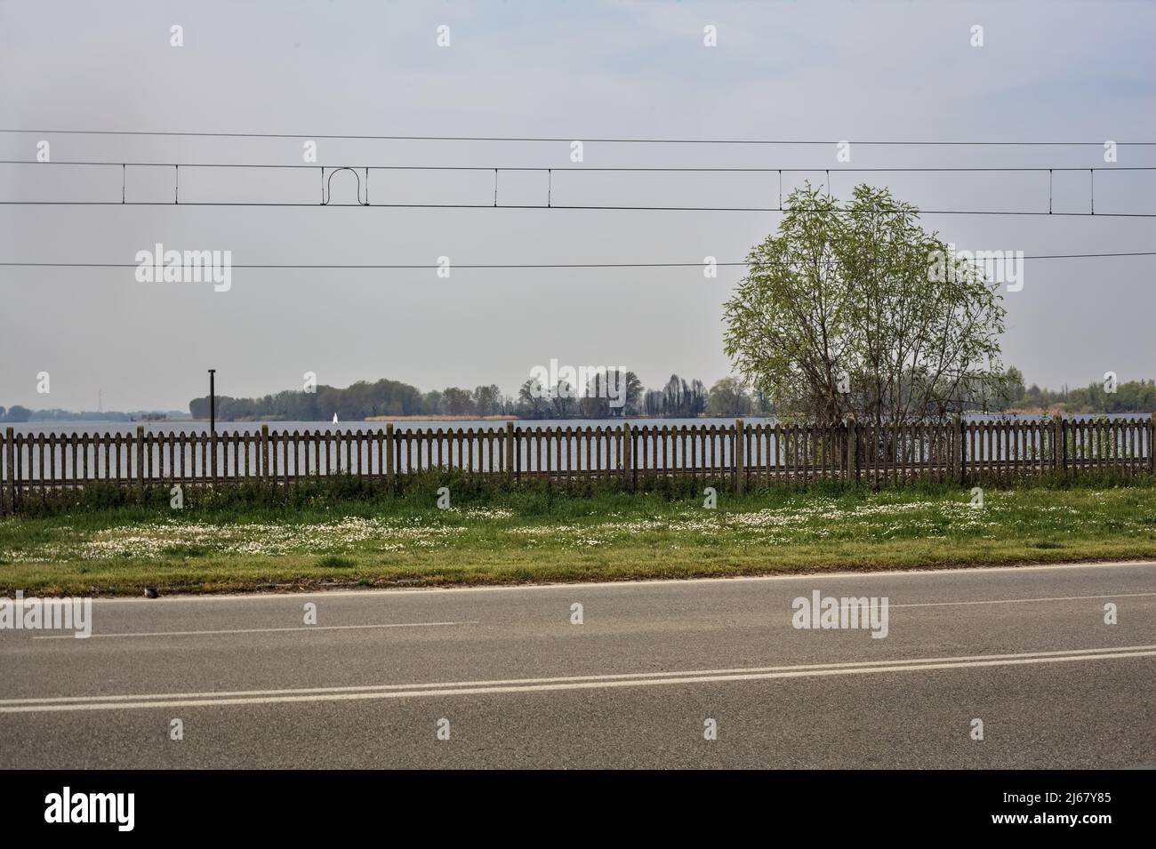 Road next to a lake and a park with railroad tracks by its edge on a ...