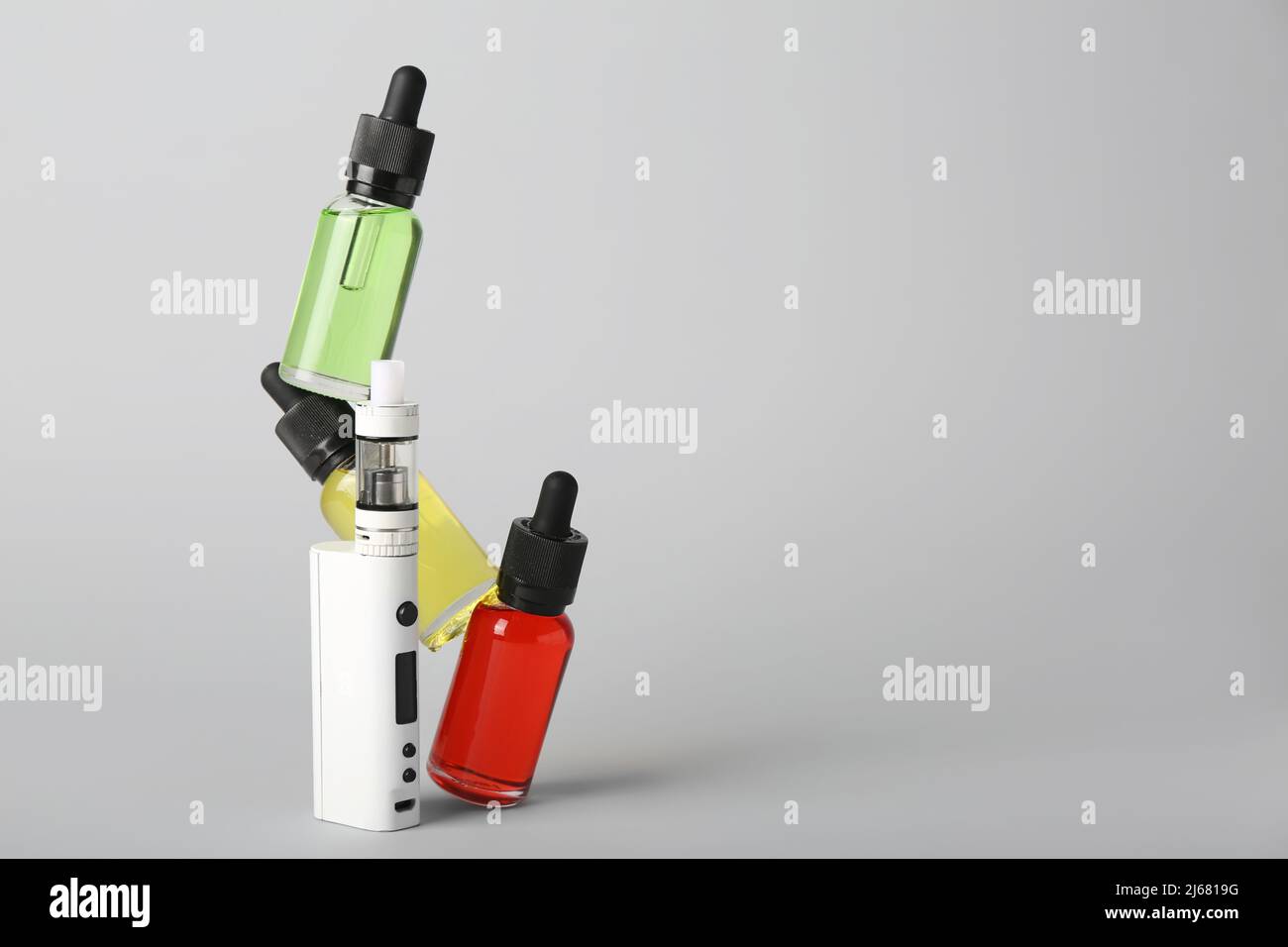 Modern vape mod and oils on grey background Stock Photo - Alamy