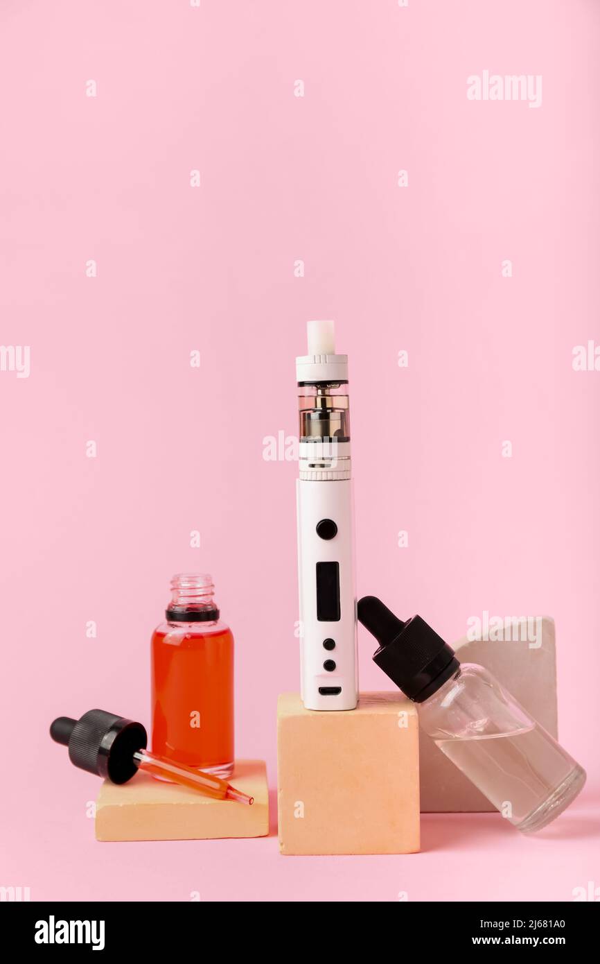 Modern vape mod and oil on pink background Stock Photo - Alamy