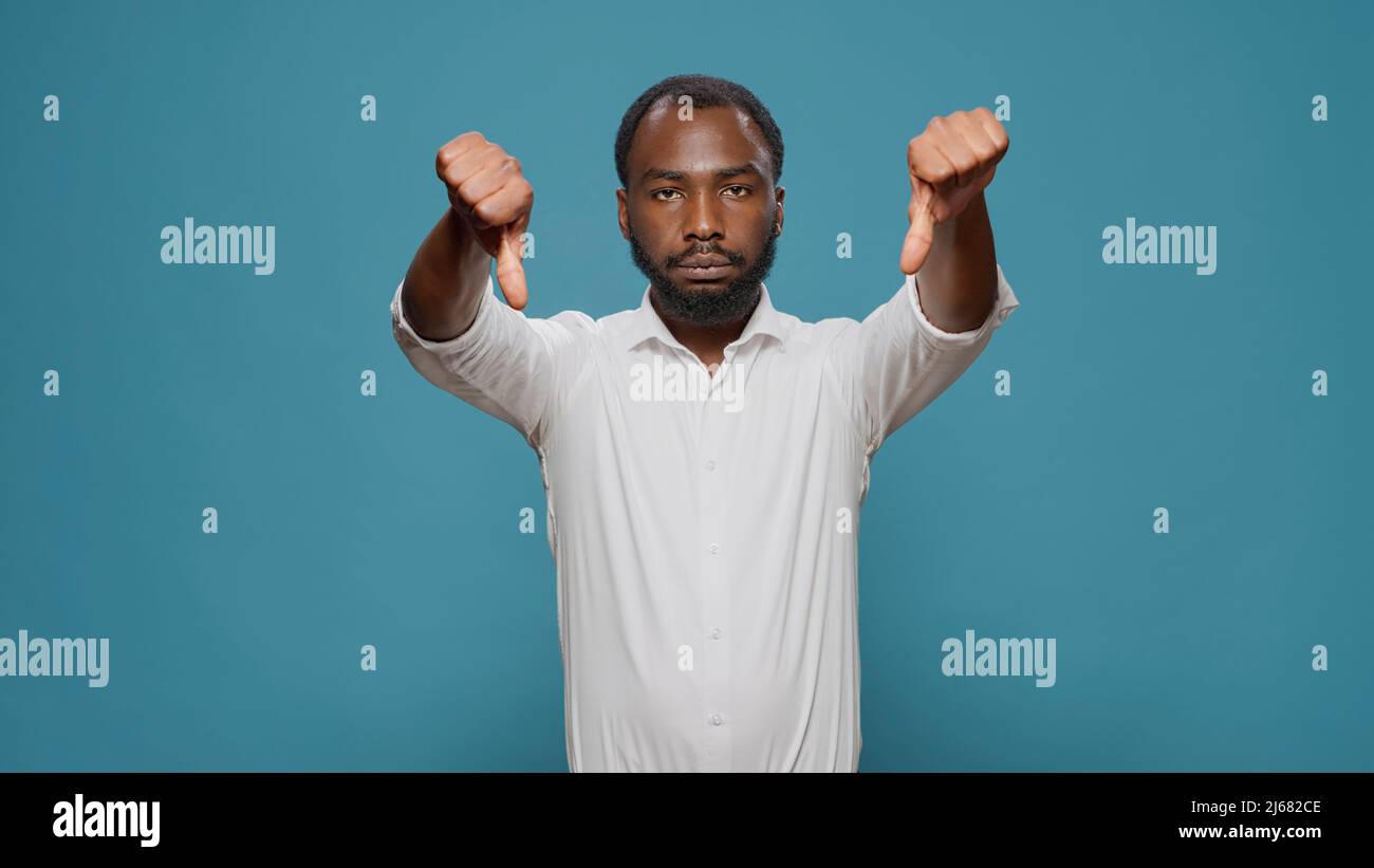 Displeased upset man showing thumbs down gesture, advertising rejection ...