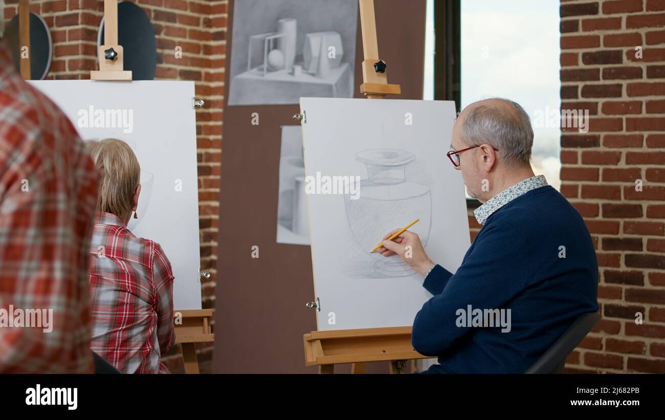 Elder man and woman drawing on canvas in art class, attending ...