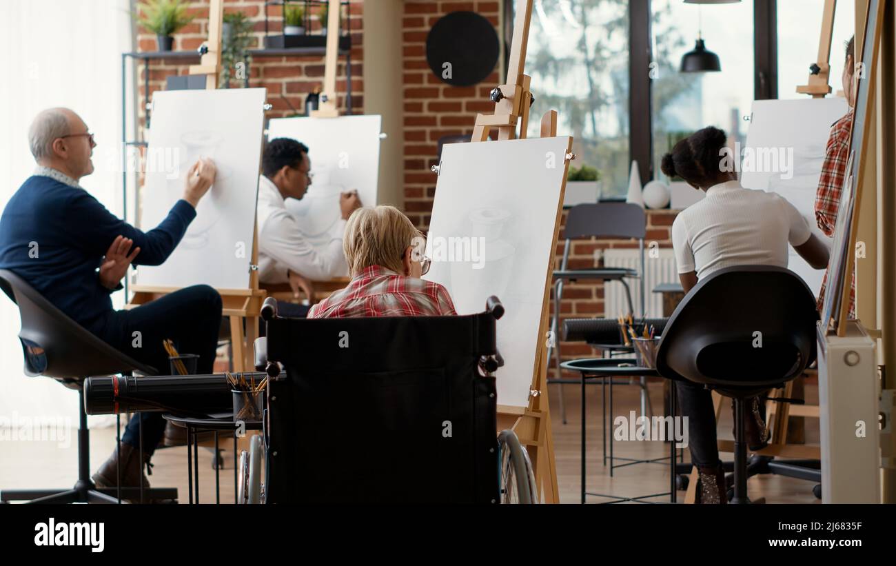 Old woman with disability using pencil to draw vase artwork, attending ...