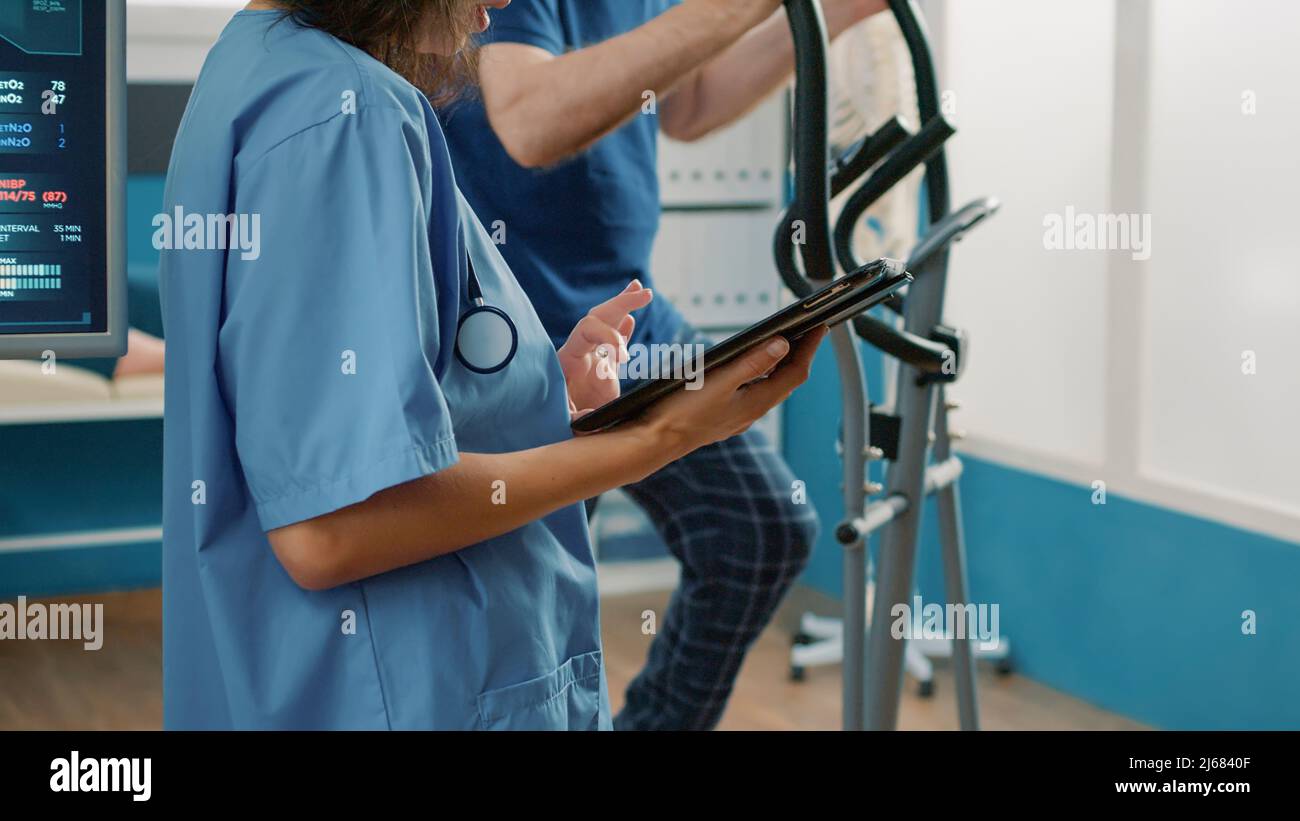 Female nurse using digital tablet and assisting elder patient at ...