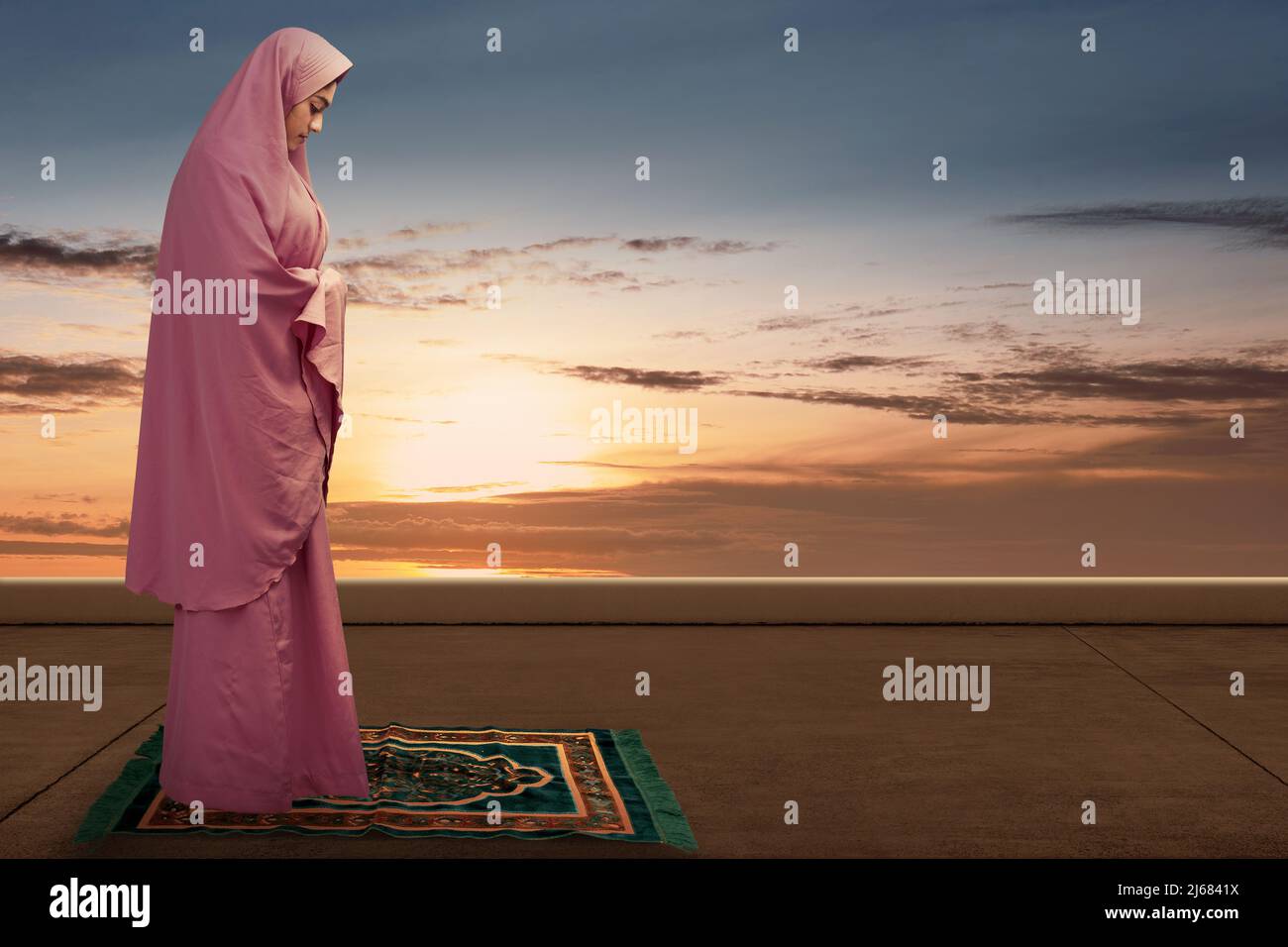 Asian Muslim woman in veil in praying position (salat) with the ...