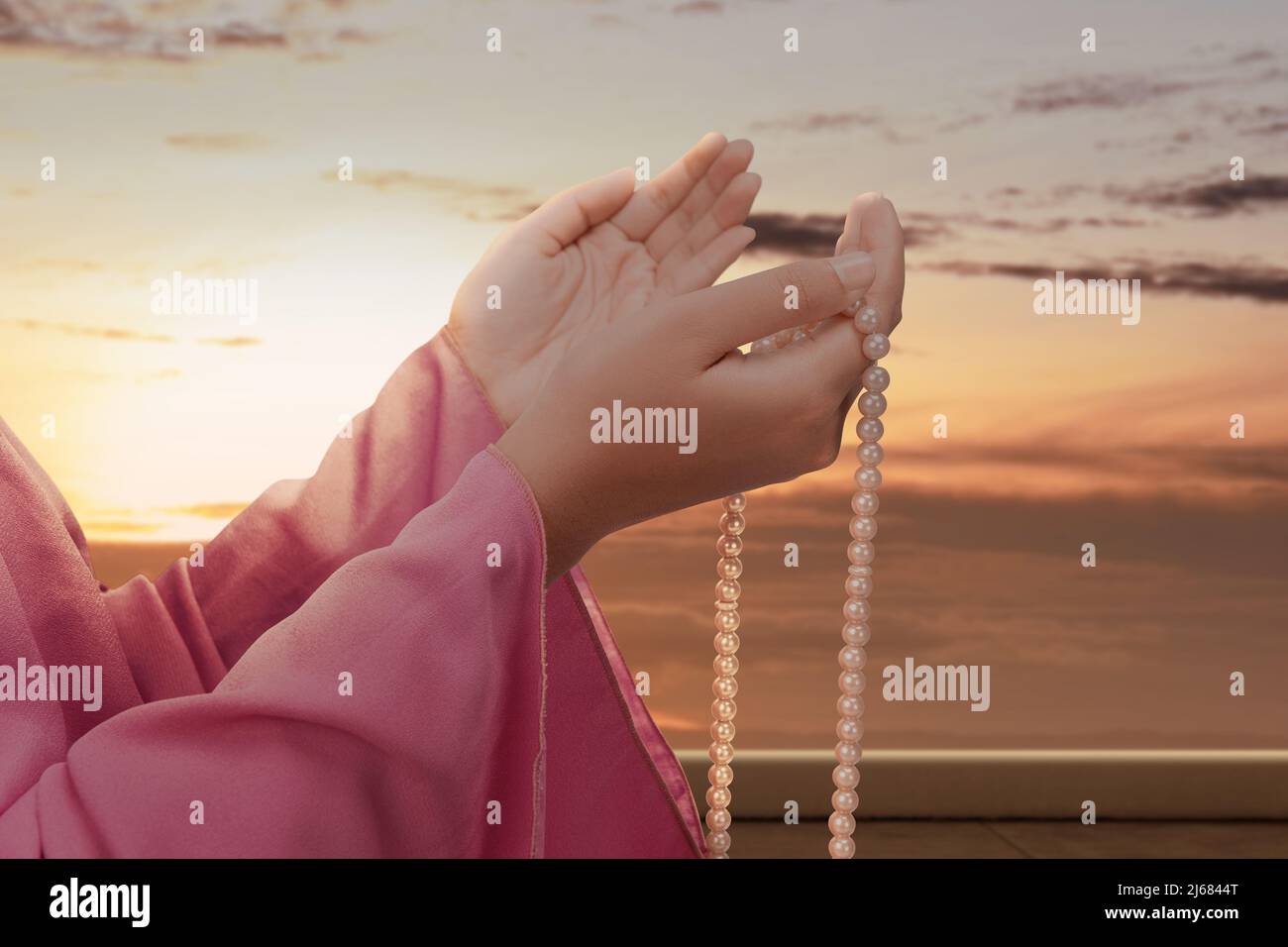 Muslim woman praying with prayer beads in her hands with the dramatic ...