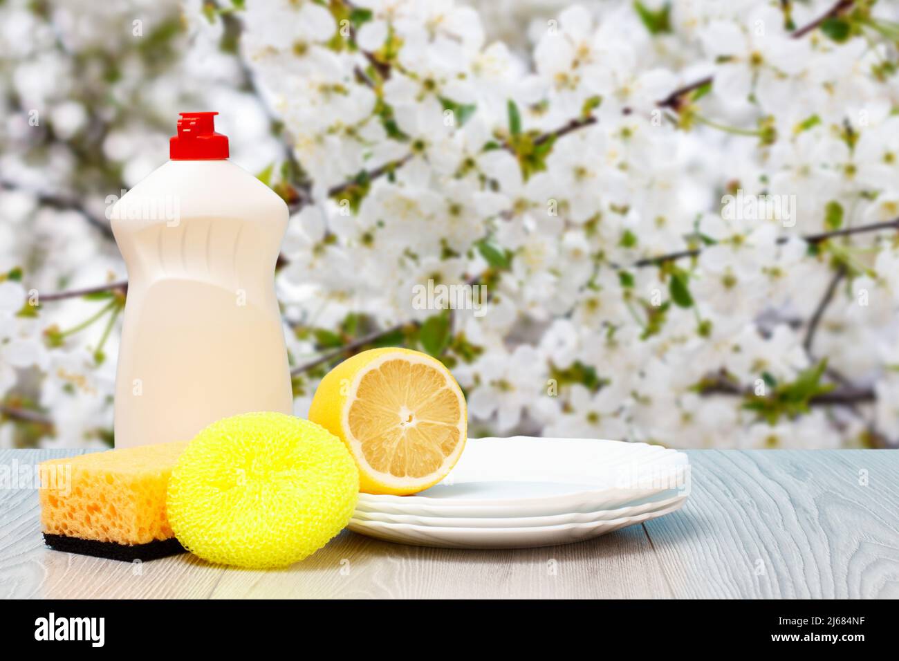 Plastic bottle of dishwashing liquid, sponges, clean plates and lemon ...