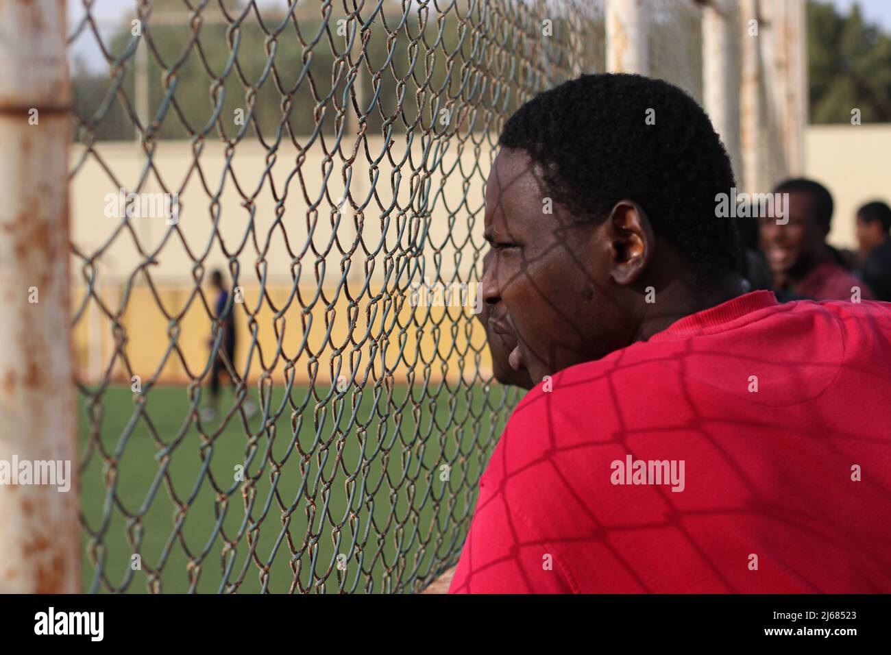A Nigerian immigrant, an inmate at Al-Sikt Prison, watches his team ...