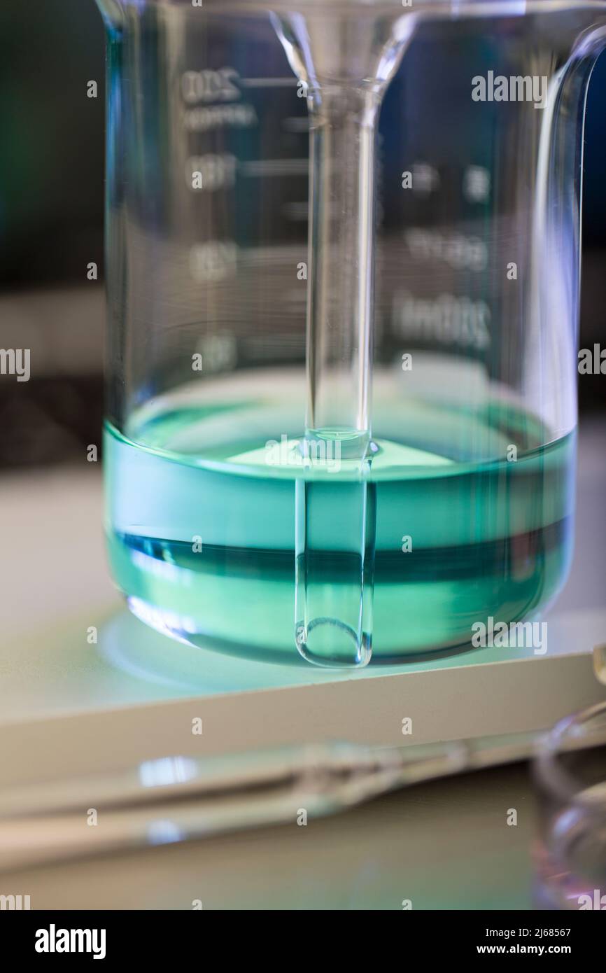 Crystal clear glass funnel in a beaker filled with blue chemical ...