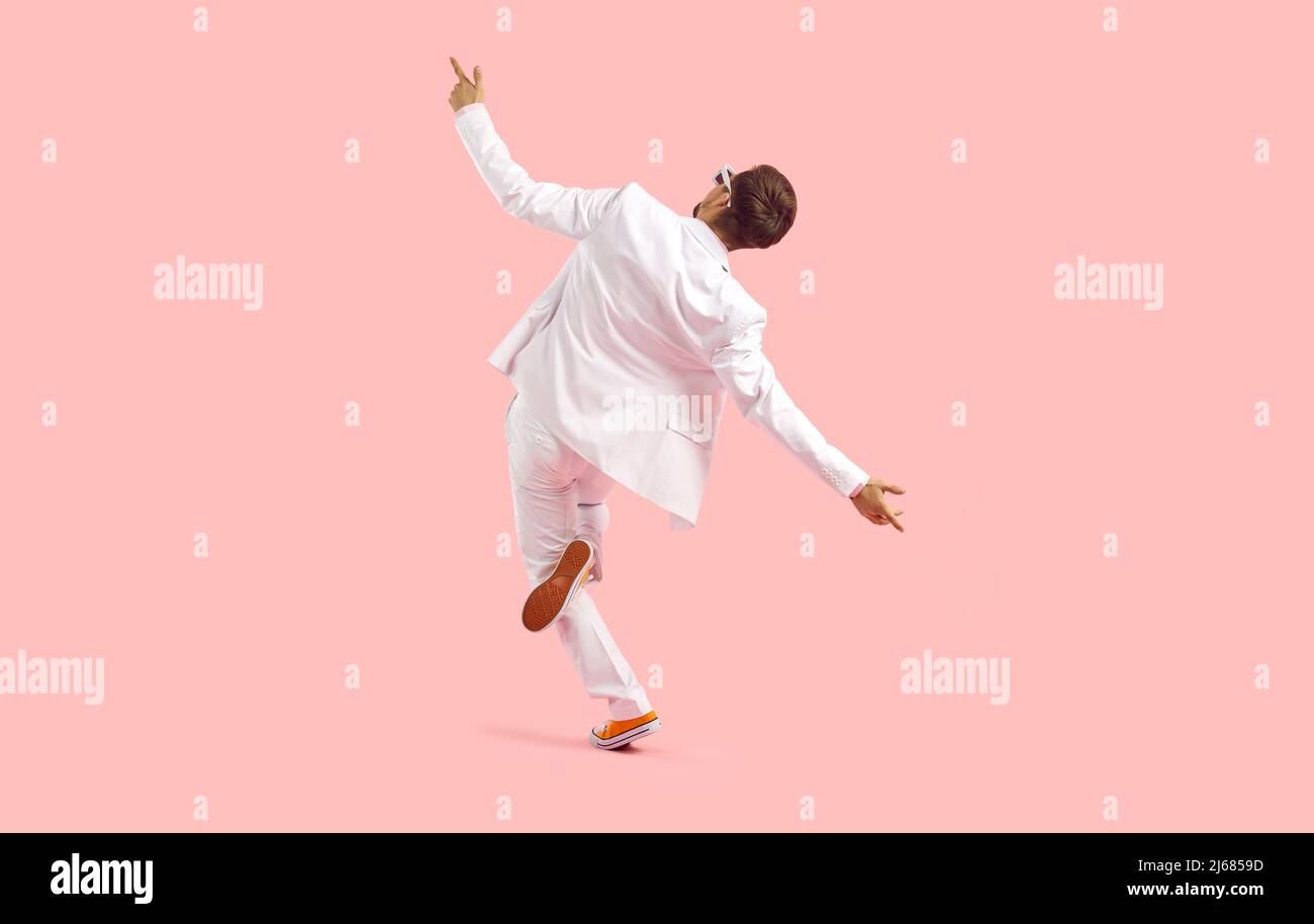 Back view of funny happy young man in white suit dancing isolated on ...