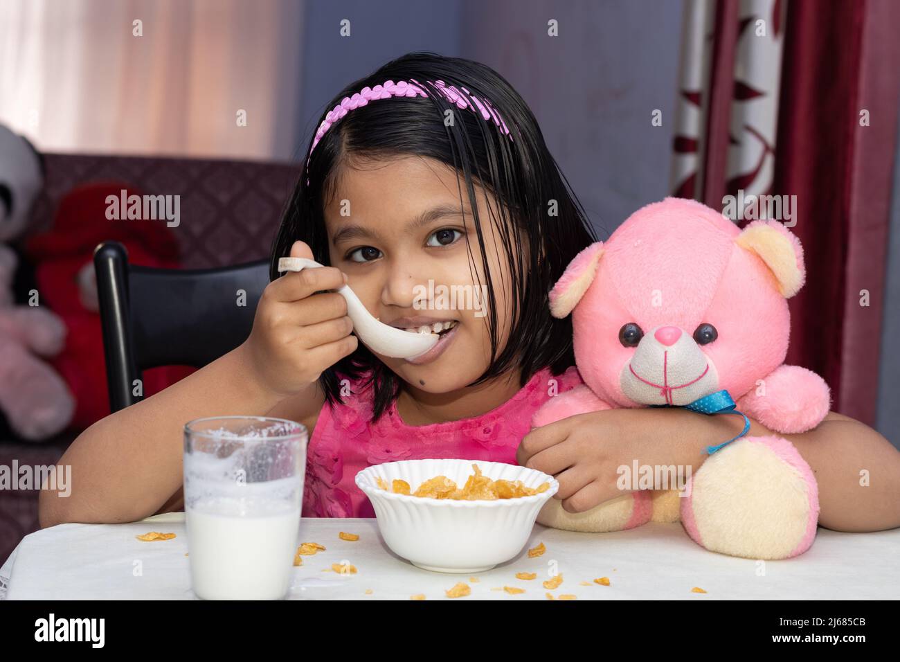 An Indian girl child eating cereal with milk with smiling face and ...