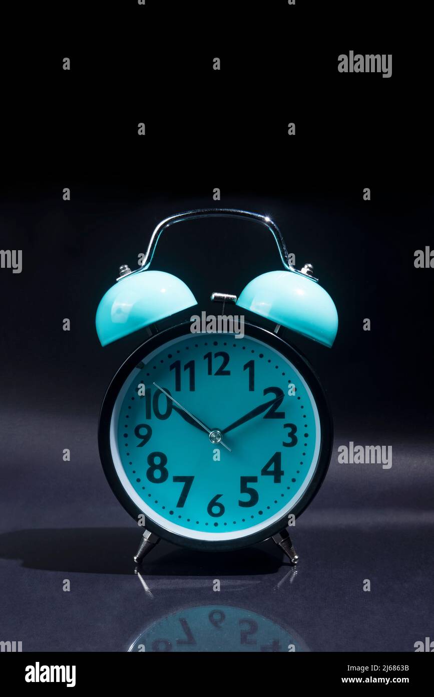 Blue alarm clock with black background Stock Photo - Alamy