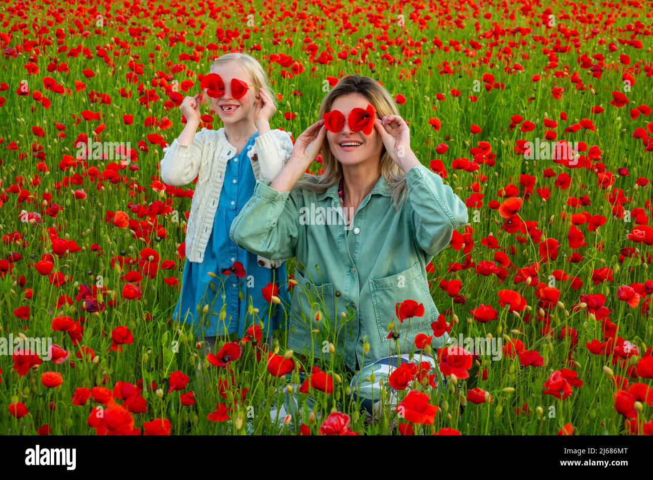 Mother with daughter on the poppies meadow. Beautiful mom and daughter ...