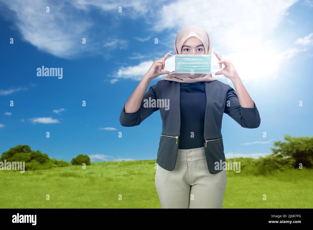 Asian Muslim woman in a headscarf and wearing a face mask while ...