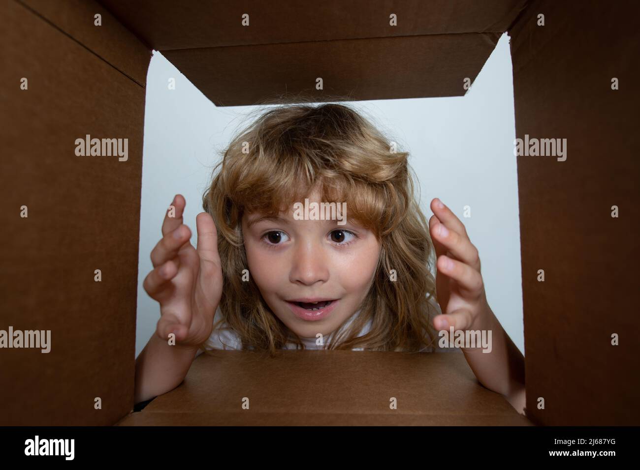Child boy opening a carton box and looking inside, unpacking concept ...