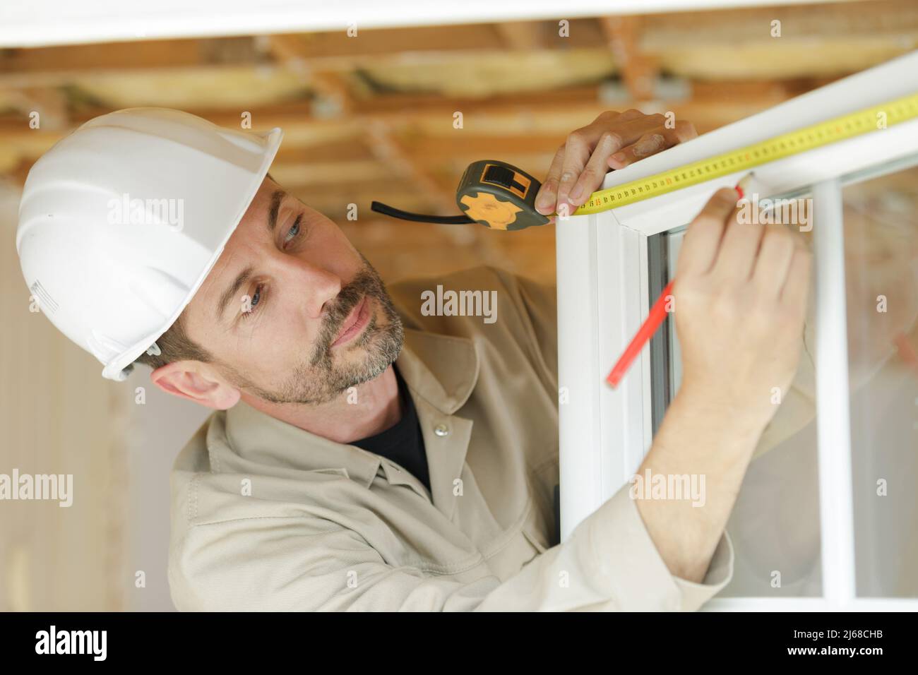 male builder measuring a window Stock Photo - Alamy