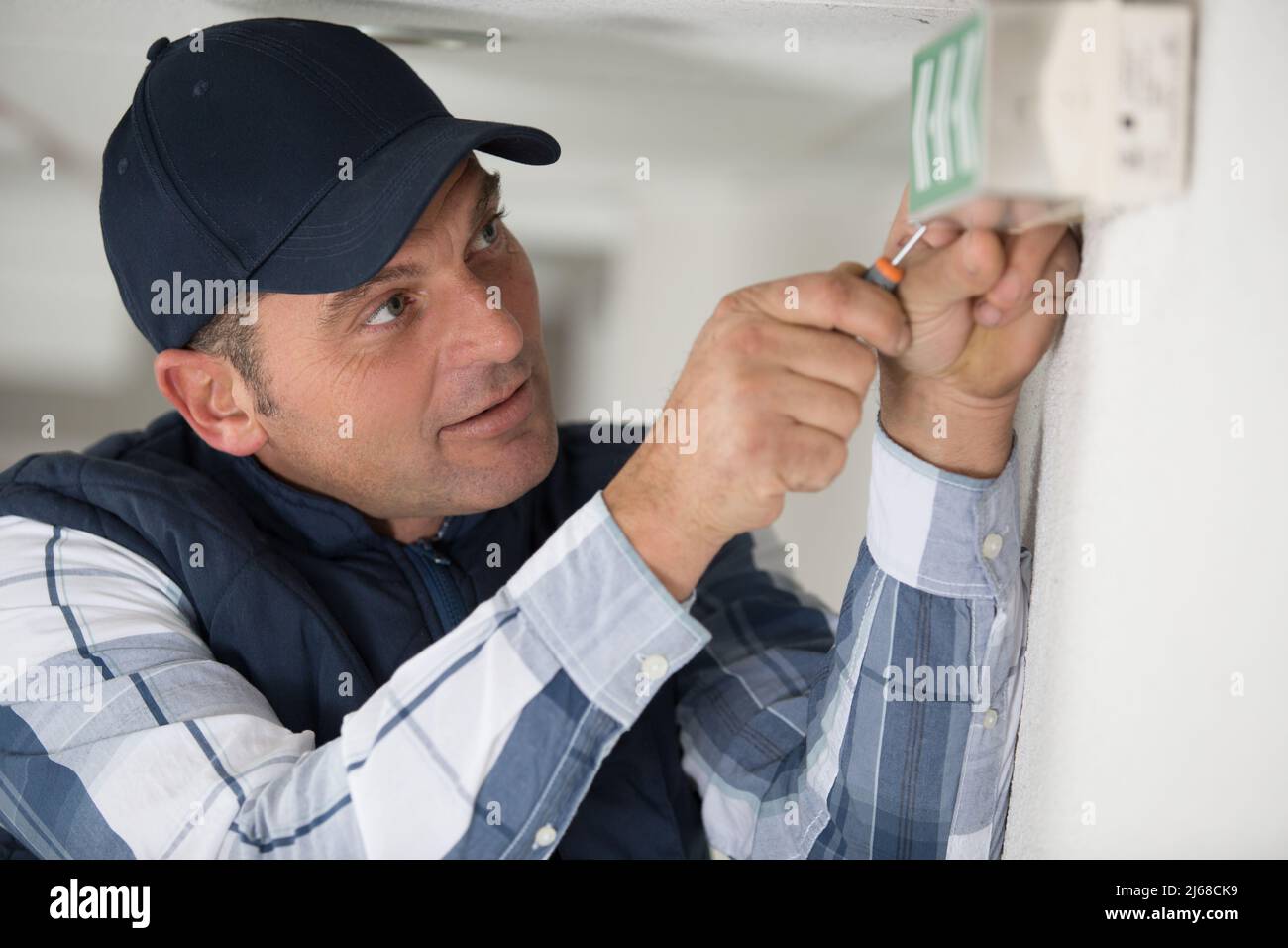 man fixing exit sign to wall Stock Photo - Alamy