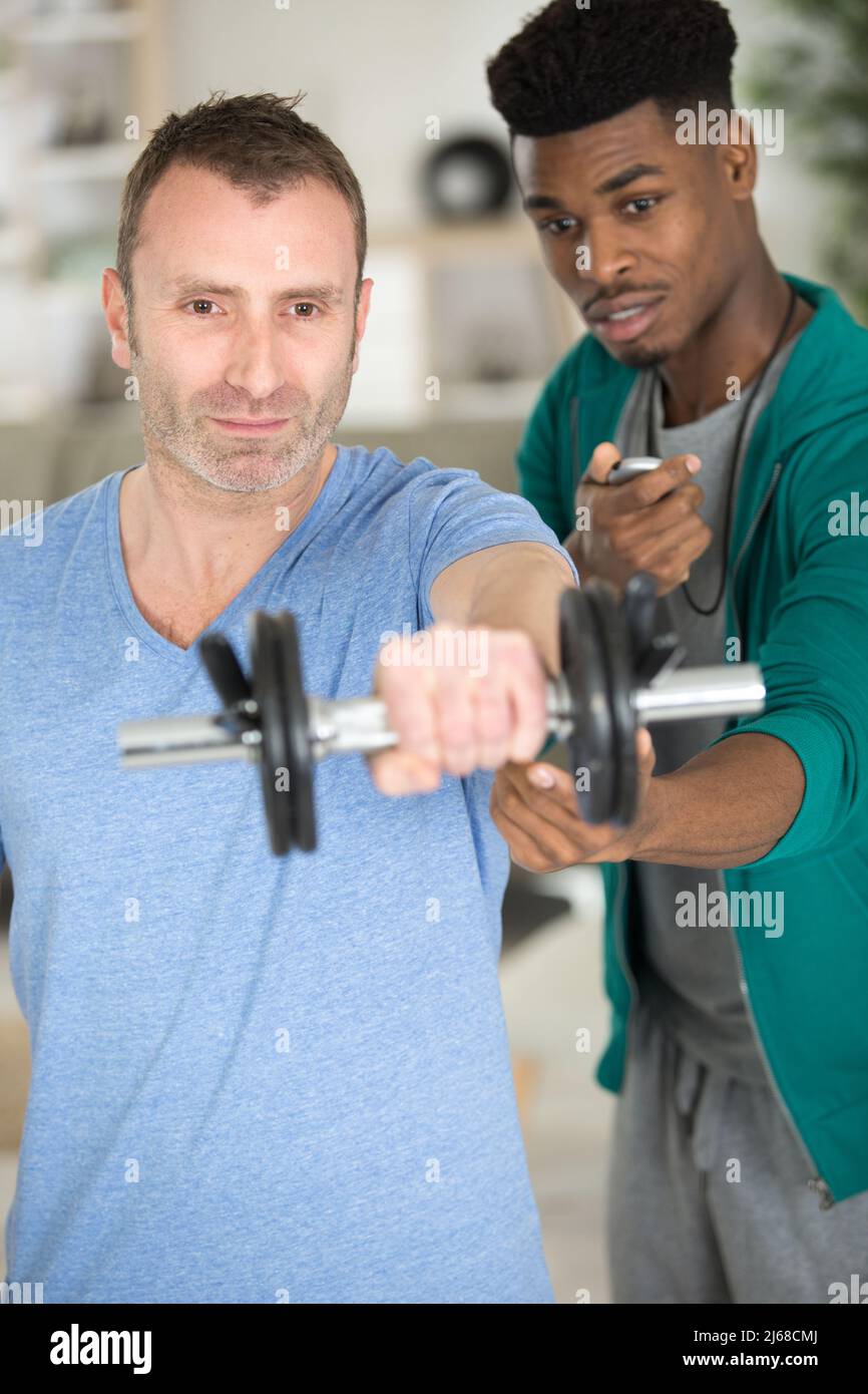 professional gym trainer motivating client to lift dumbbell Stock Photo ...