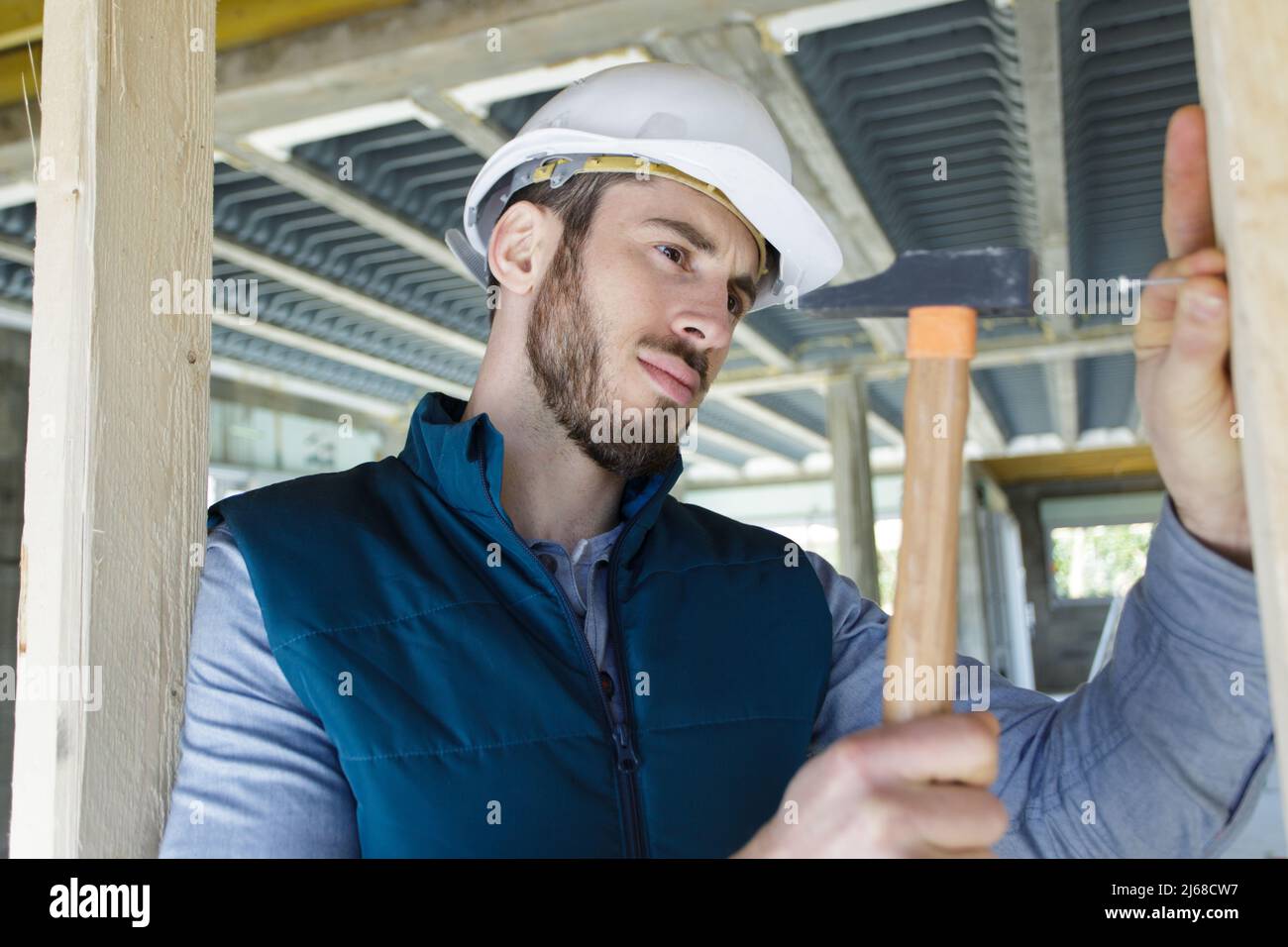 builder knocking nail into wall with hammer Stock Photo - Alamy