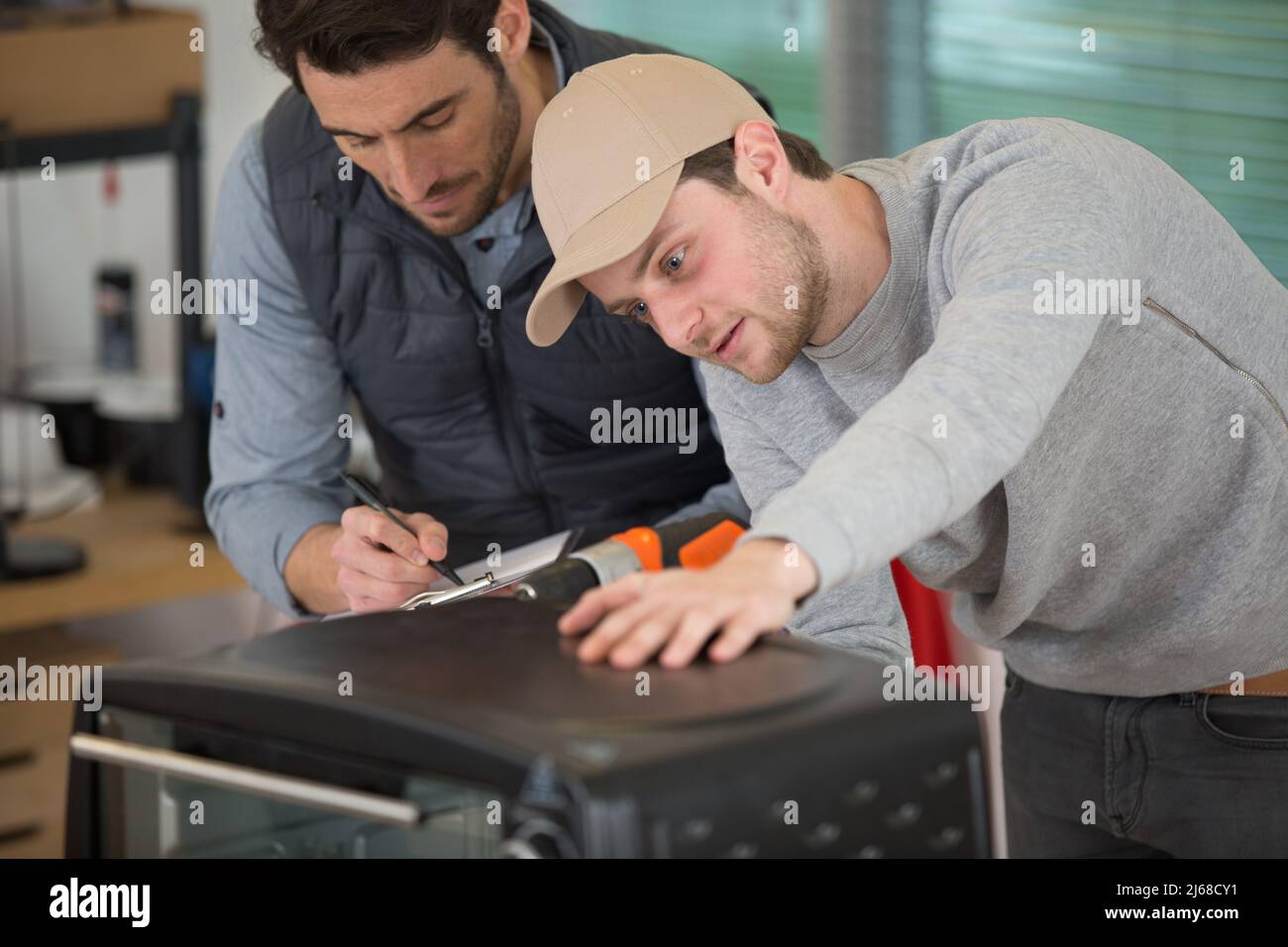 a male technician repairing a printer with apprentice Stock Photo - Alamy