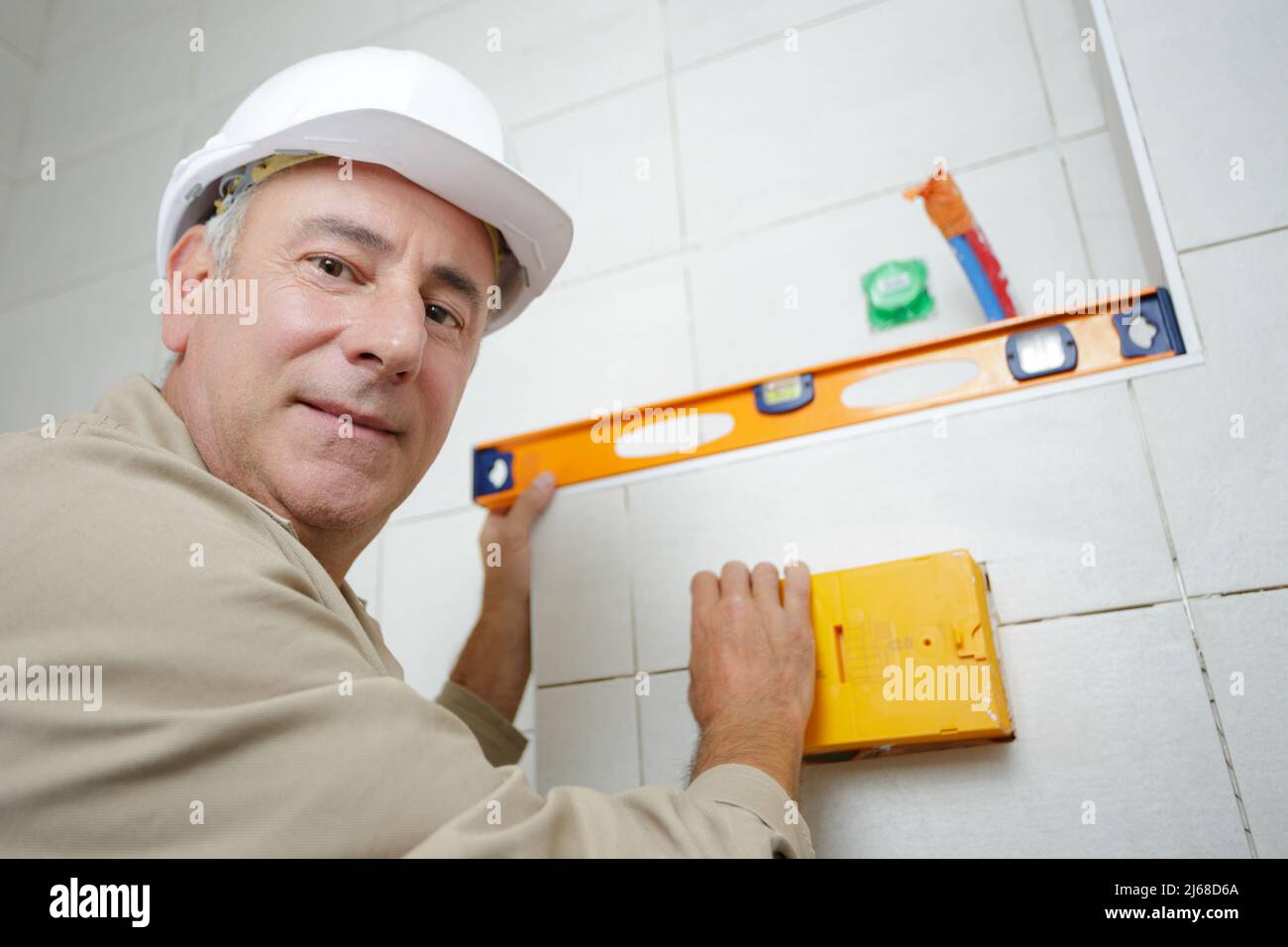 happy professional worker measuring wall with level Stock Photo - Alamy