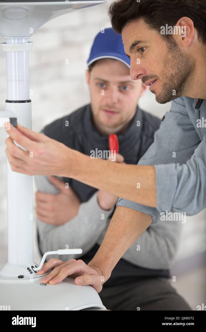 close-up of two men fixing a chair Stock Photo - Alamy