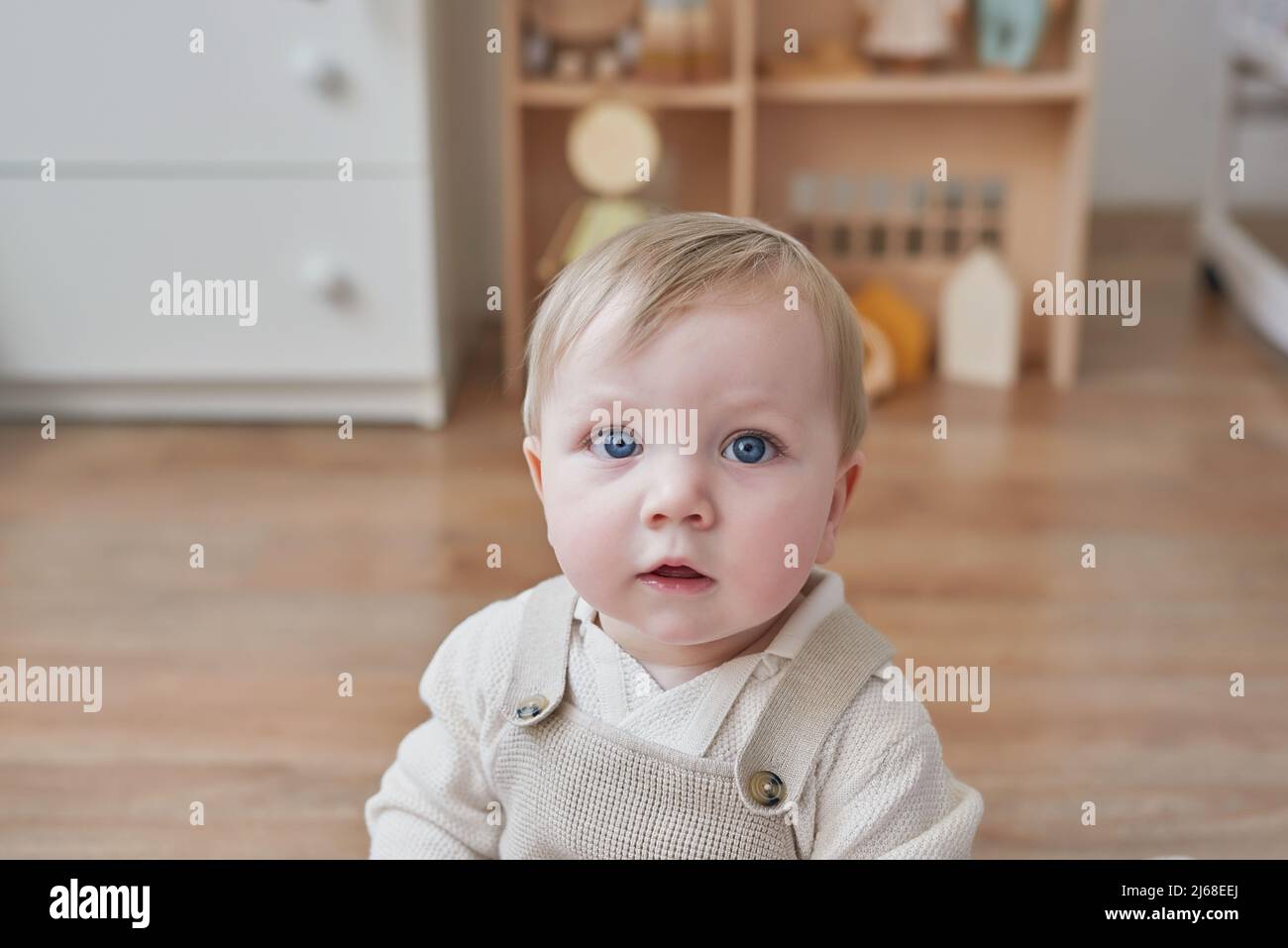 Wonderful baby boy with blue eyes. Child playing with toys in nursery ...