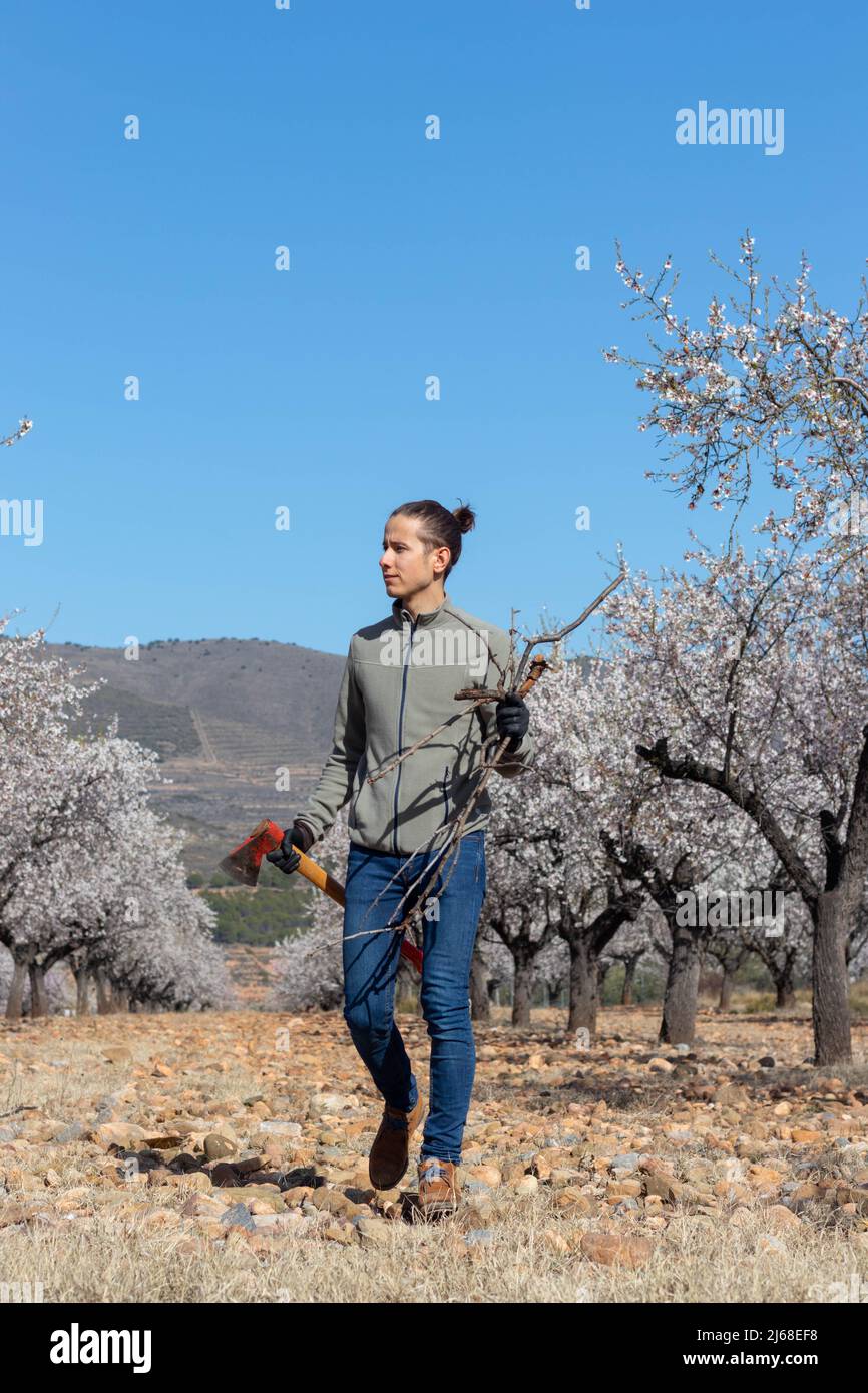Young man with firewood to prepare a barbecue in spring surrounded by ...